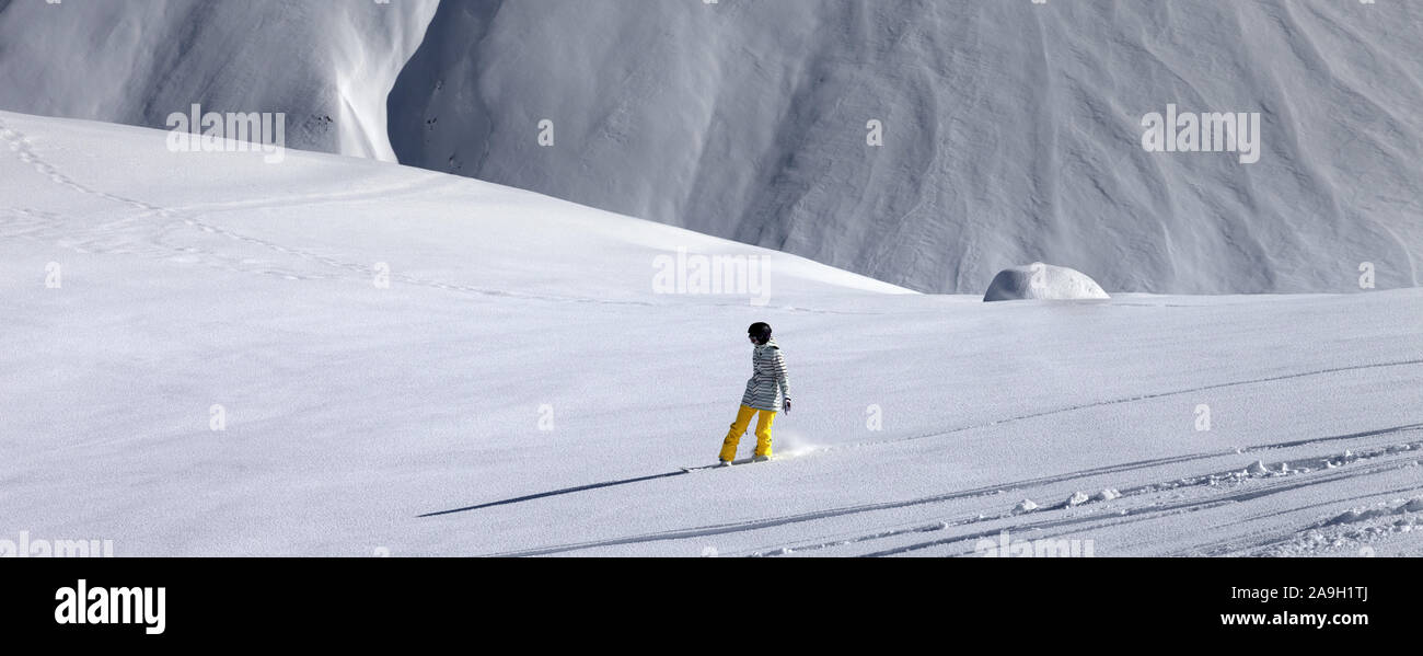 Snowboarder downhill on snowy off piste slope with newly-fallen snow ...