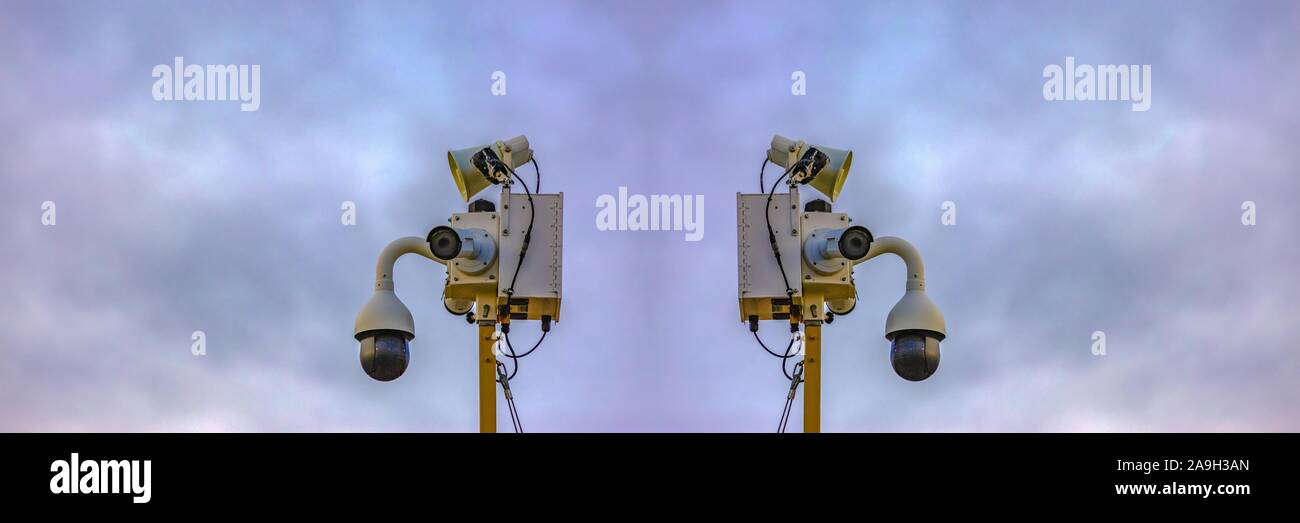 Back to back security cameras with light clouds and sky behind for copy ...