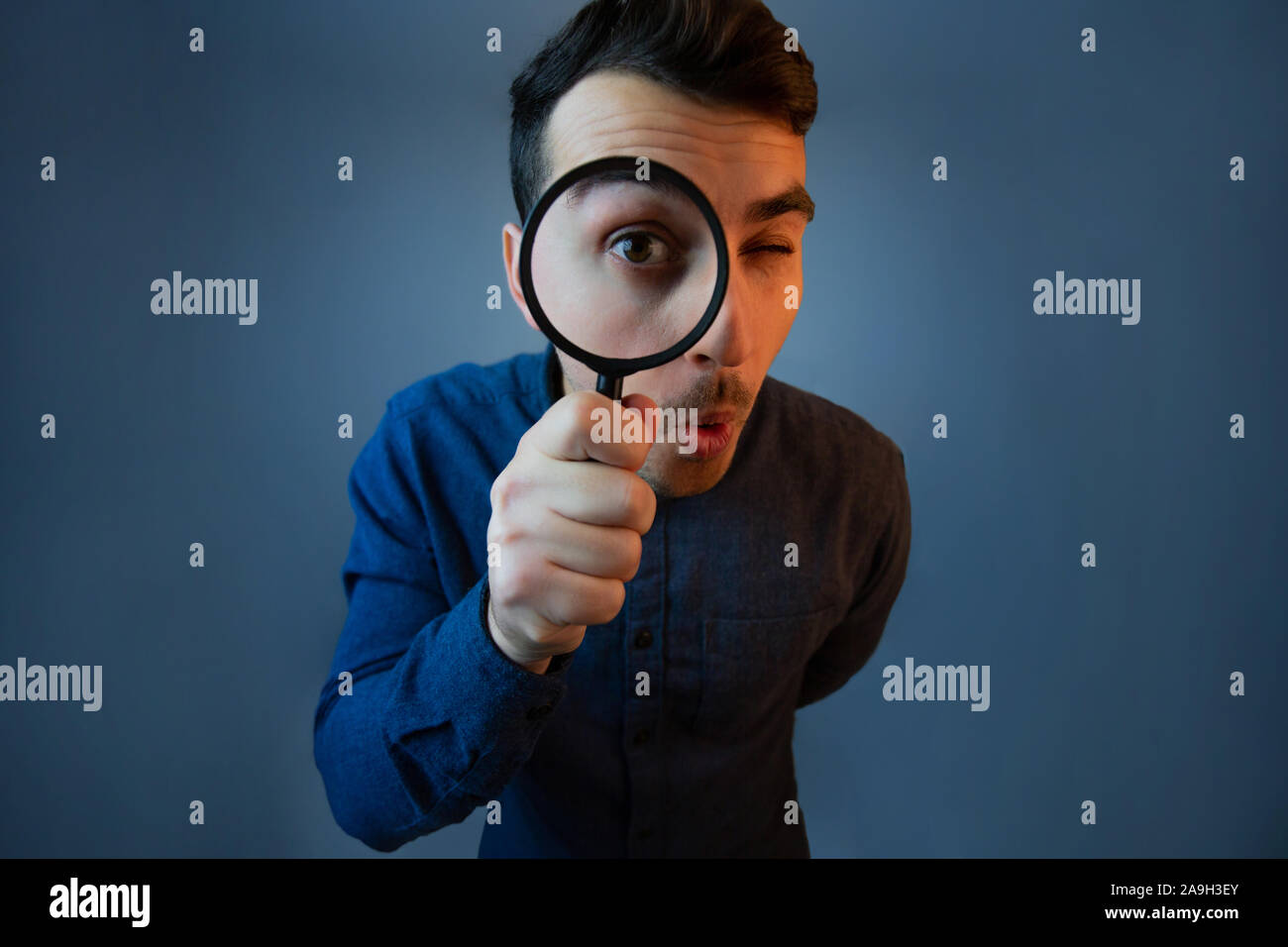 Curious young man with magnifying glass Isolated on grey background ...