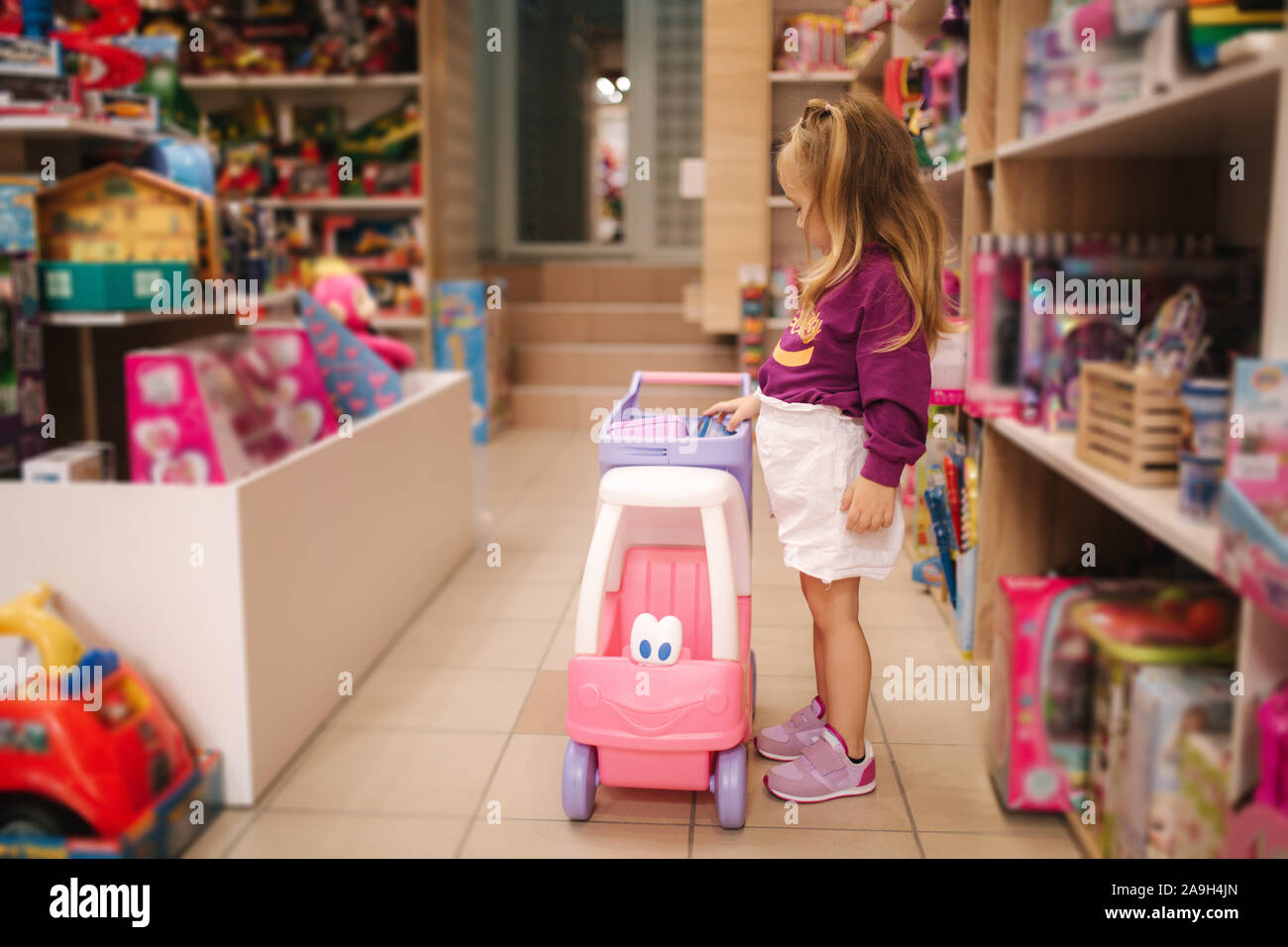 Back view of adorable little girl shopping for toys. Cute female in toy ...