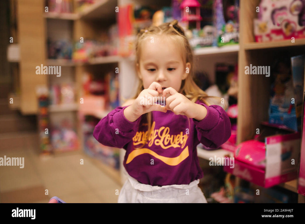 Adorable little girl shopping for toys. Cute female in toy store. Happy ...