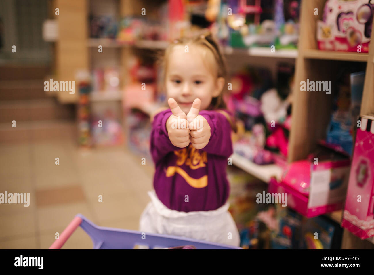 Adorable little girl shopping for toys. Cute female in toy store. Happy ...
