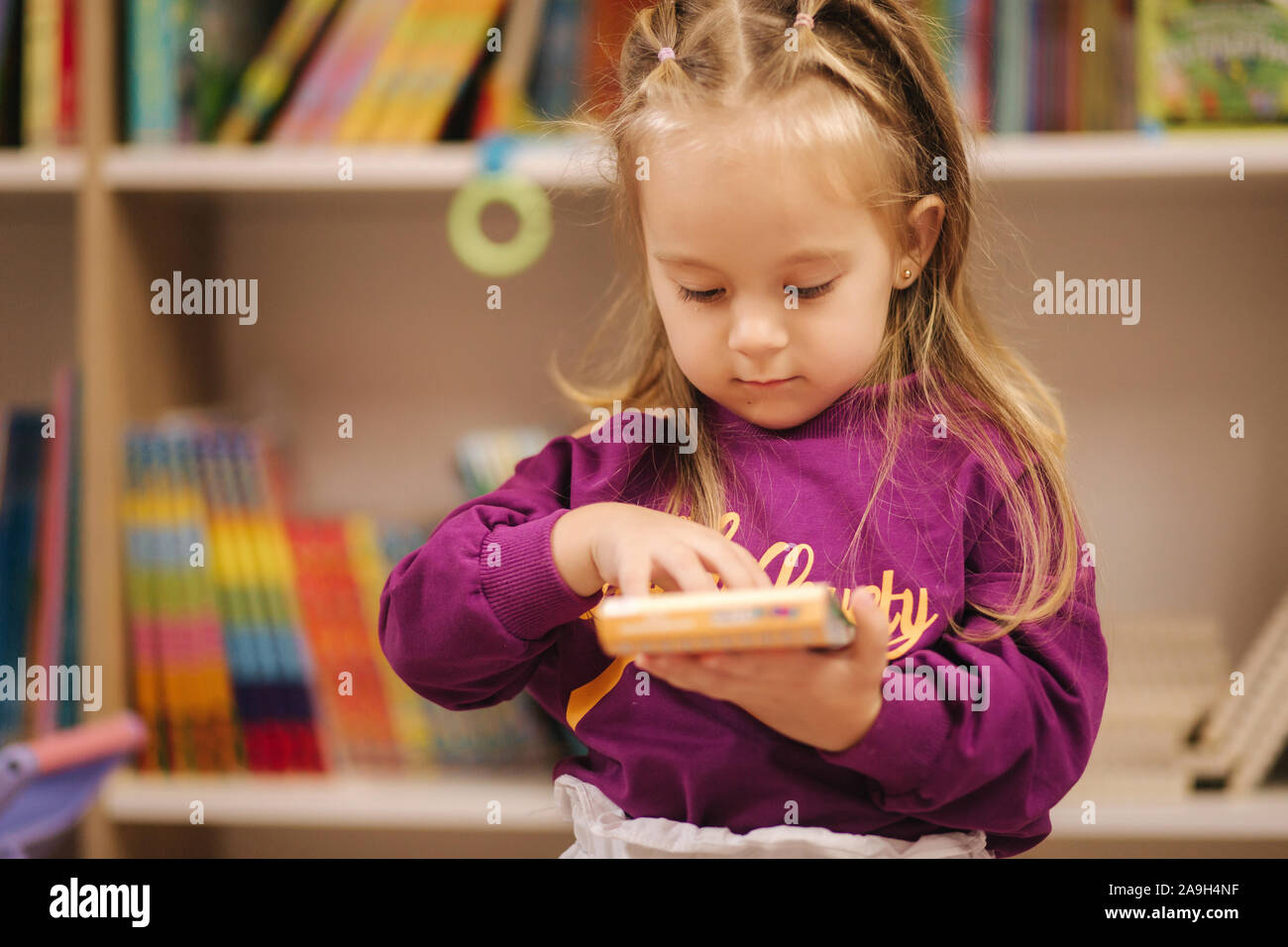 Adorable little girl shopping for toys. Cute female in toy store. Happy ...