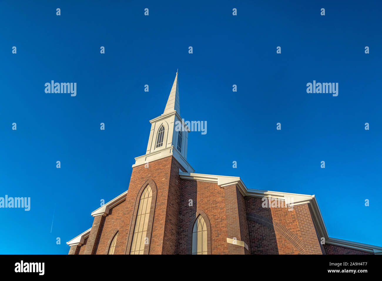 Church with classic red brick exterior wall and white steeple against ...