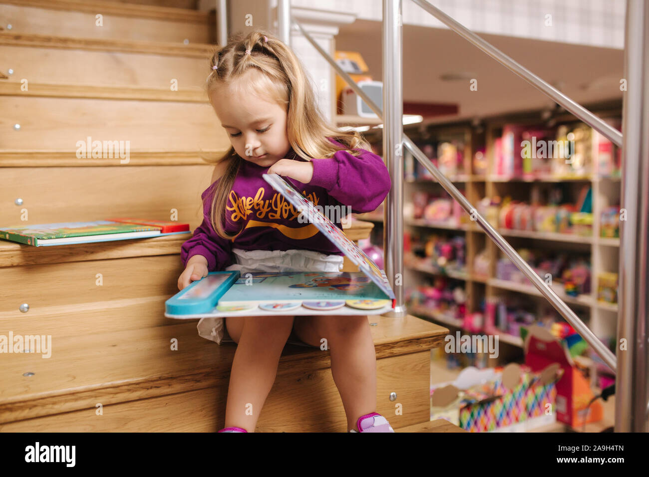 Beautiful little girl read interactive book in toy store Stock Photo ...