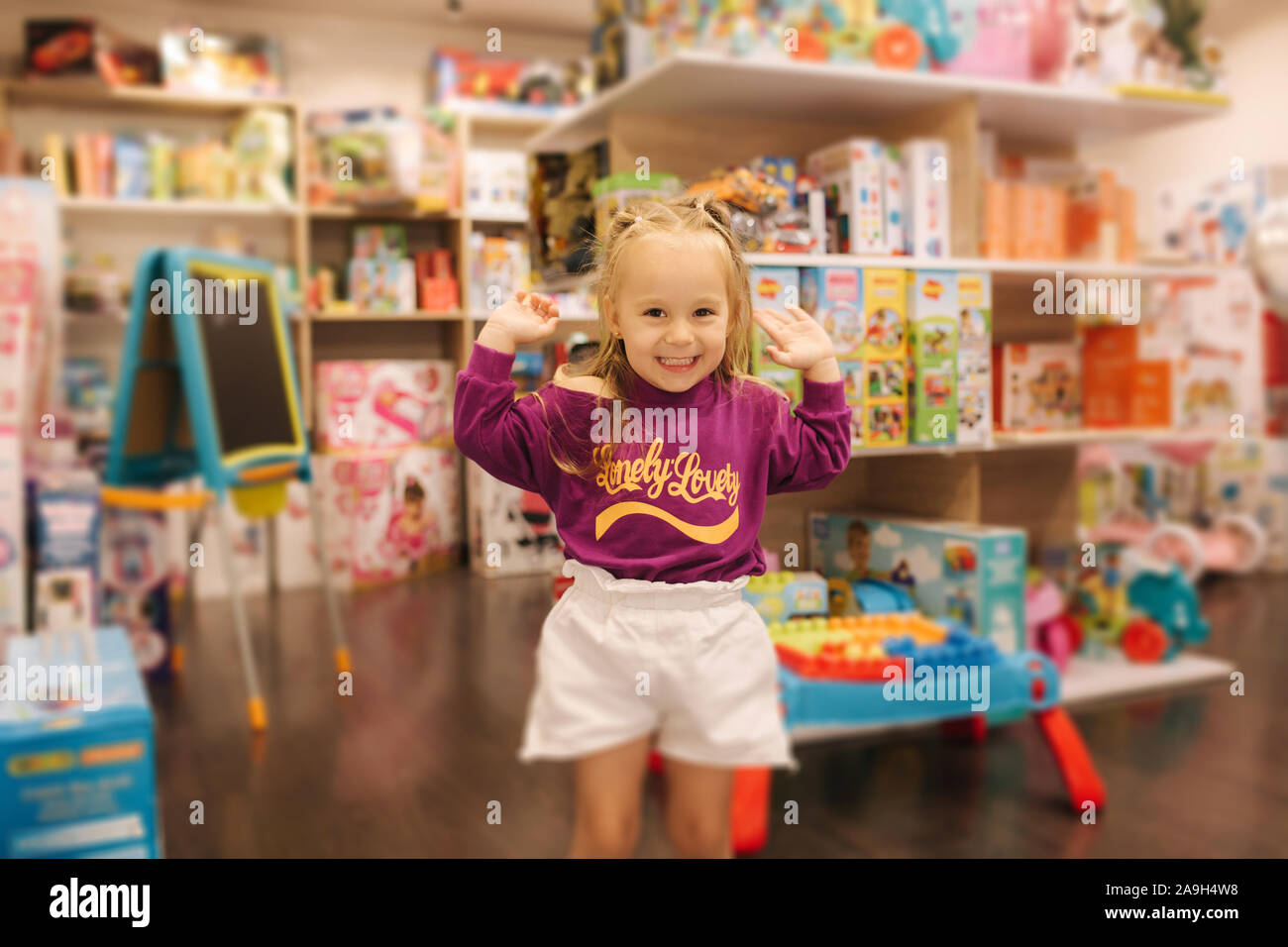 Happy little girl walkning in toy store. Cute girl choose toy. Adorable ...