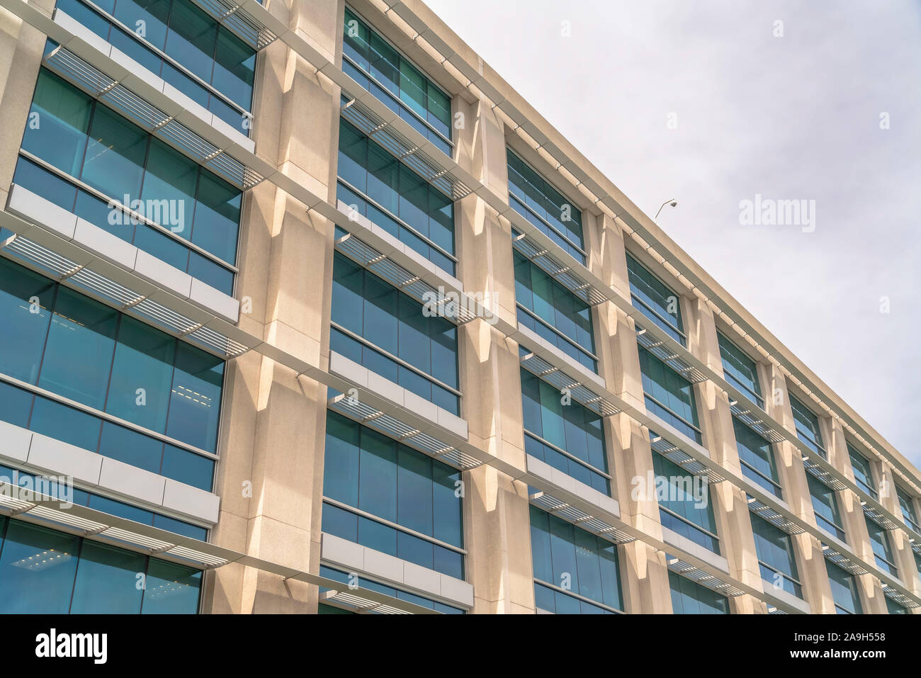 Modern building facade close up with glass windows and sunlit concrete ...