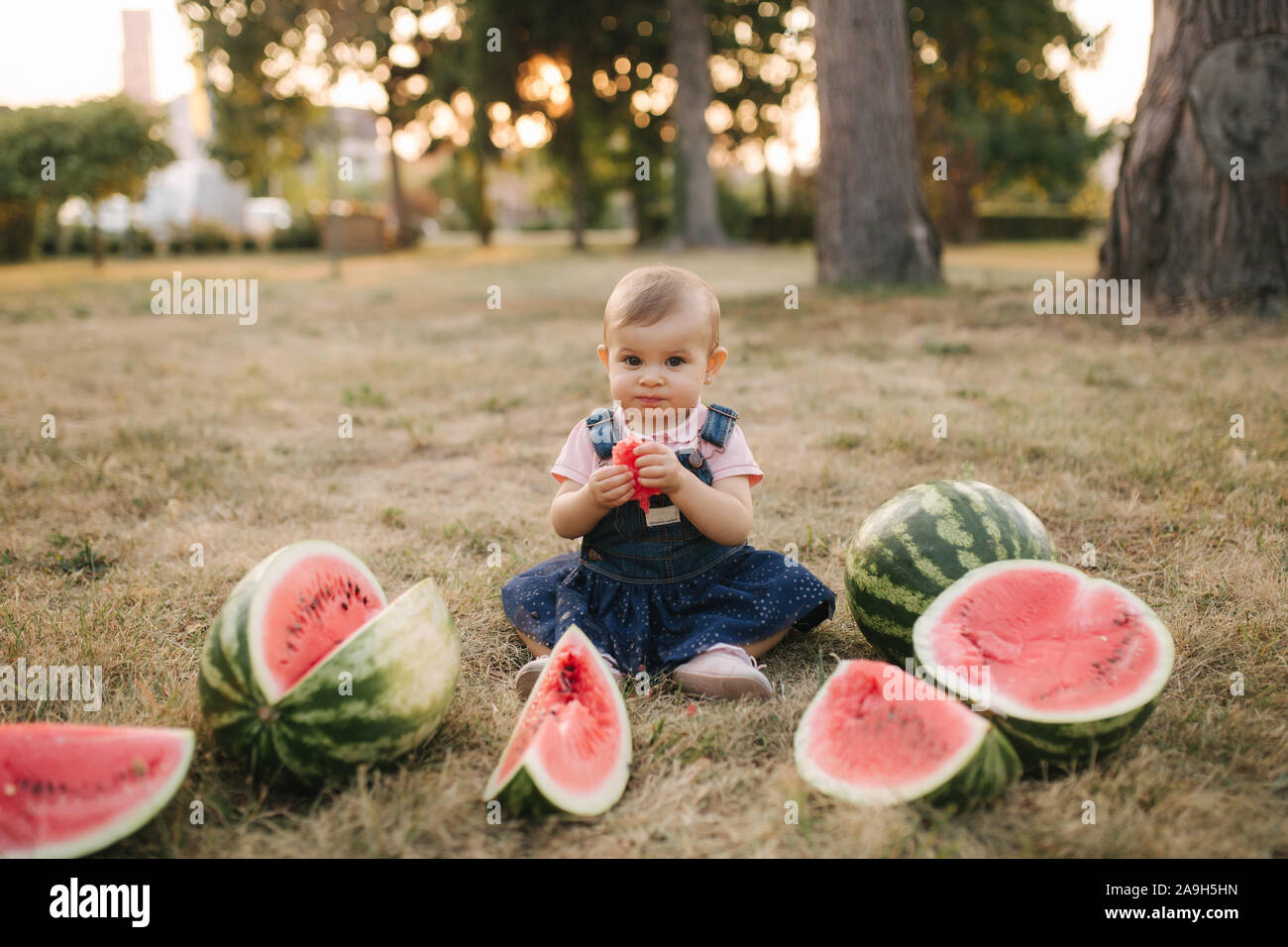 Cute little baby girl laughing with watermelons. Girl dressed in denim ...