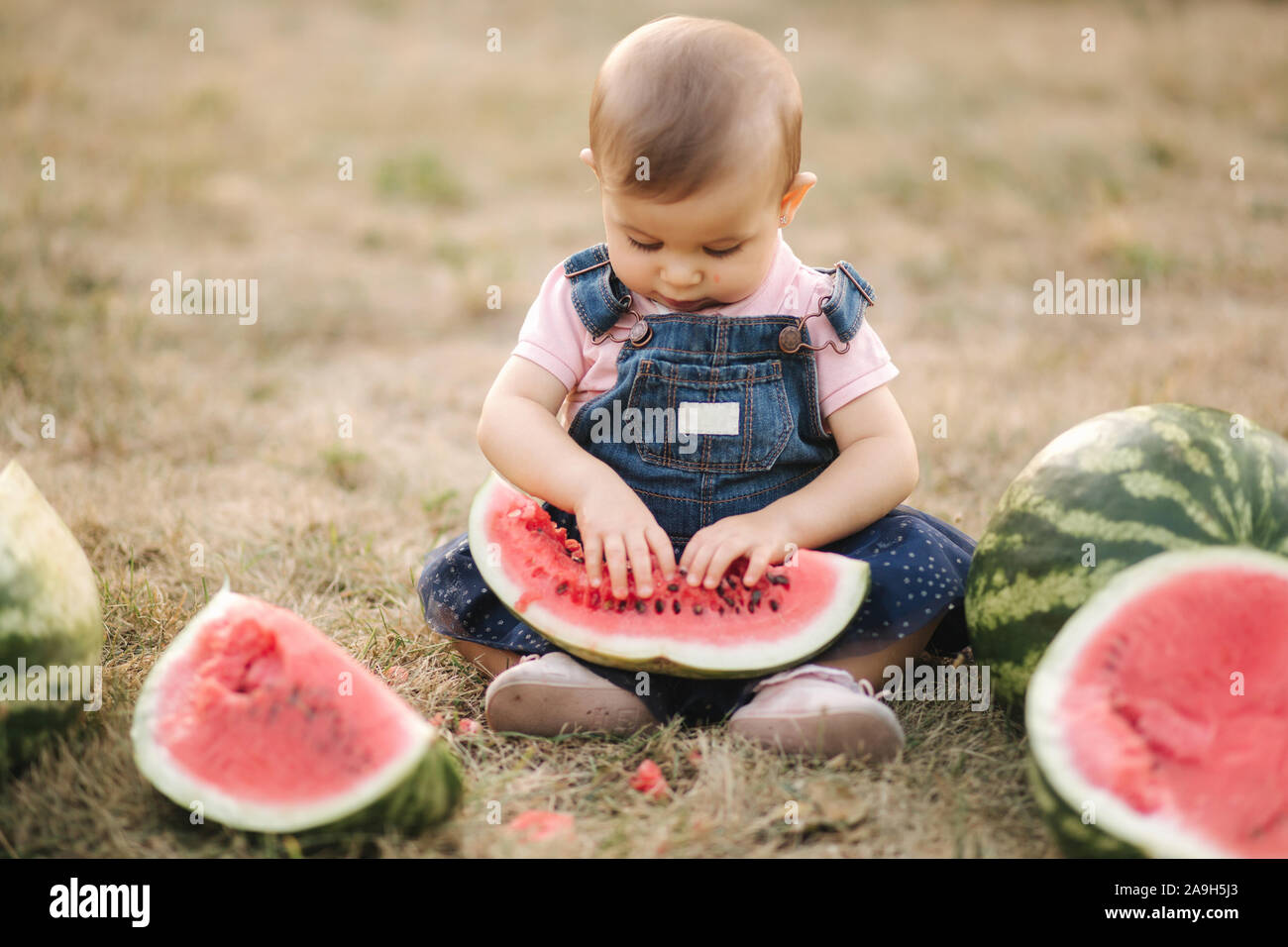 Cute little baby girl laughing with watermelons. Girl dressed in denim ...