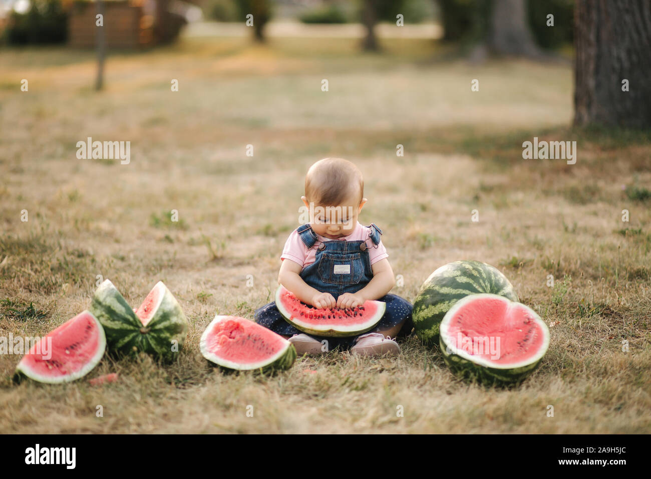 Cute little baby girl laughing with watermelons. Girl dressed in denim ...