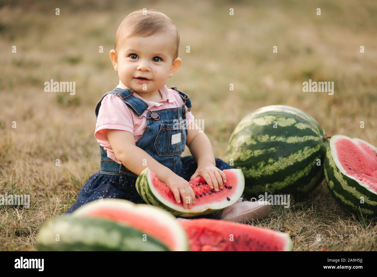 Cute little baby girl laughing with watermelons. Girl dressed in denim ...