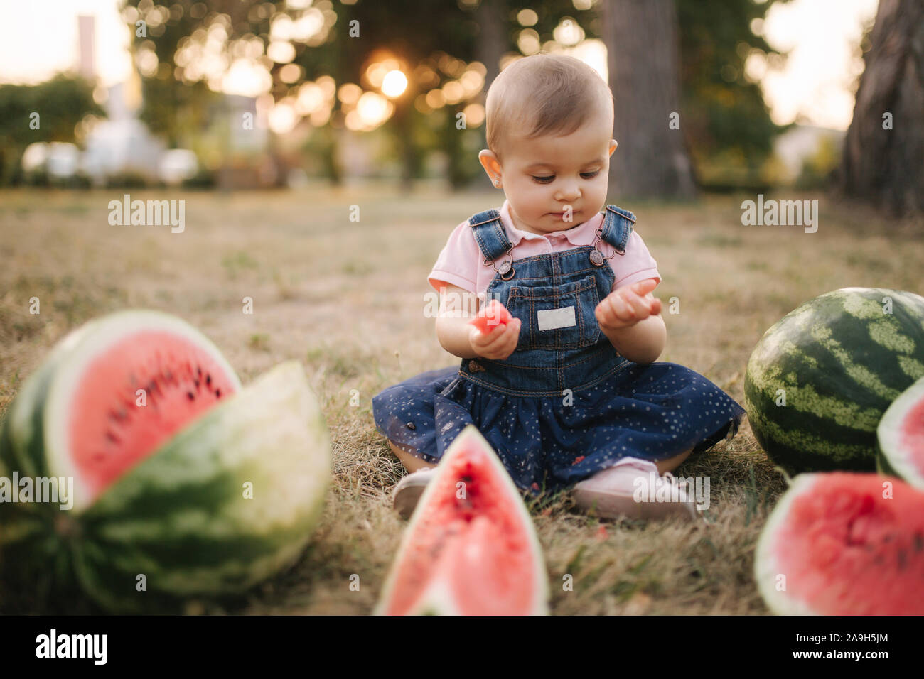 Cute little baby girl laughing with watermelons. Girl dressed in denim ...