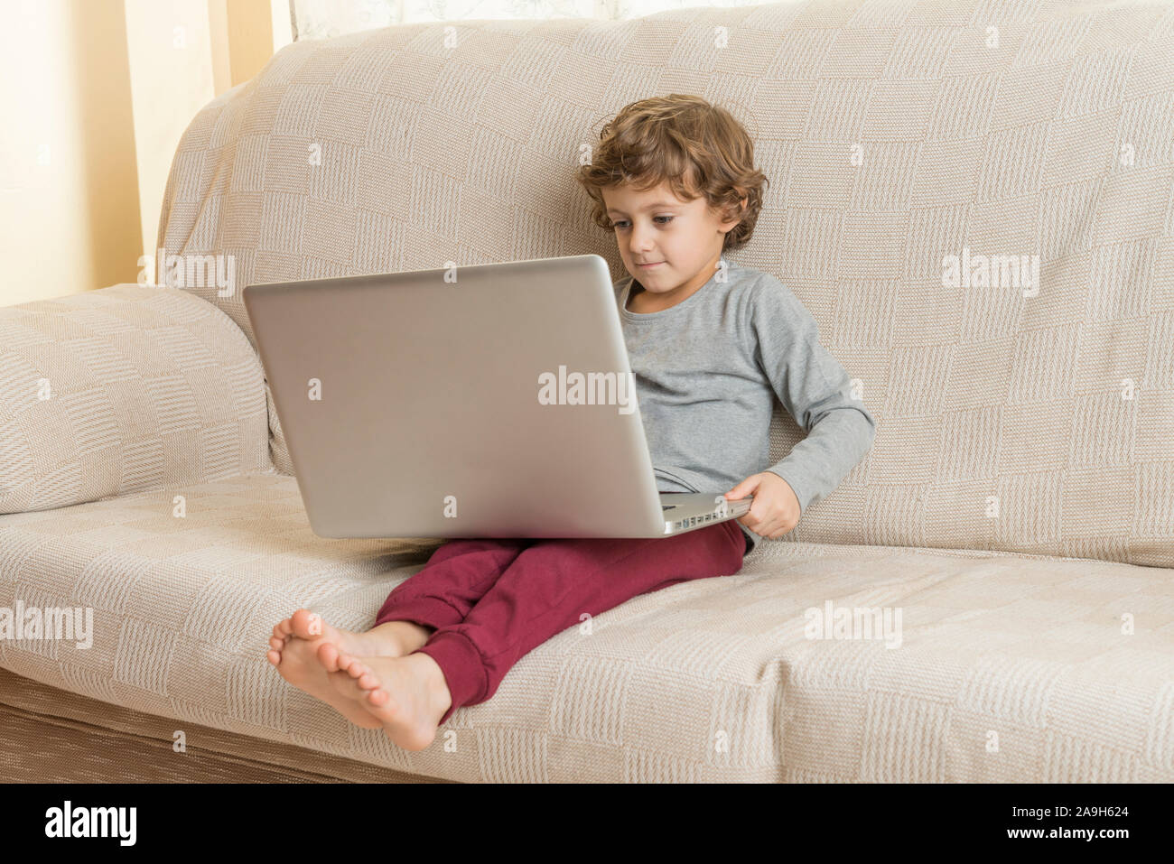 Child sitting on a sofa watching a laptop. Technology concept in ...
