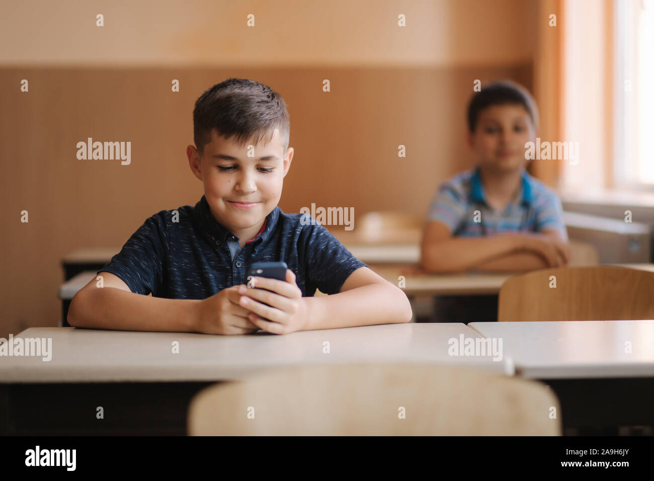 Cute little boy use phone during lesson. Two schollboy in class Stock ...