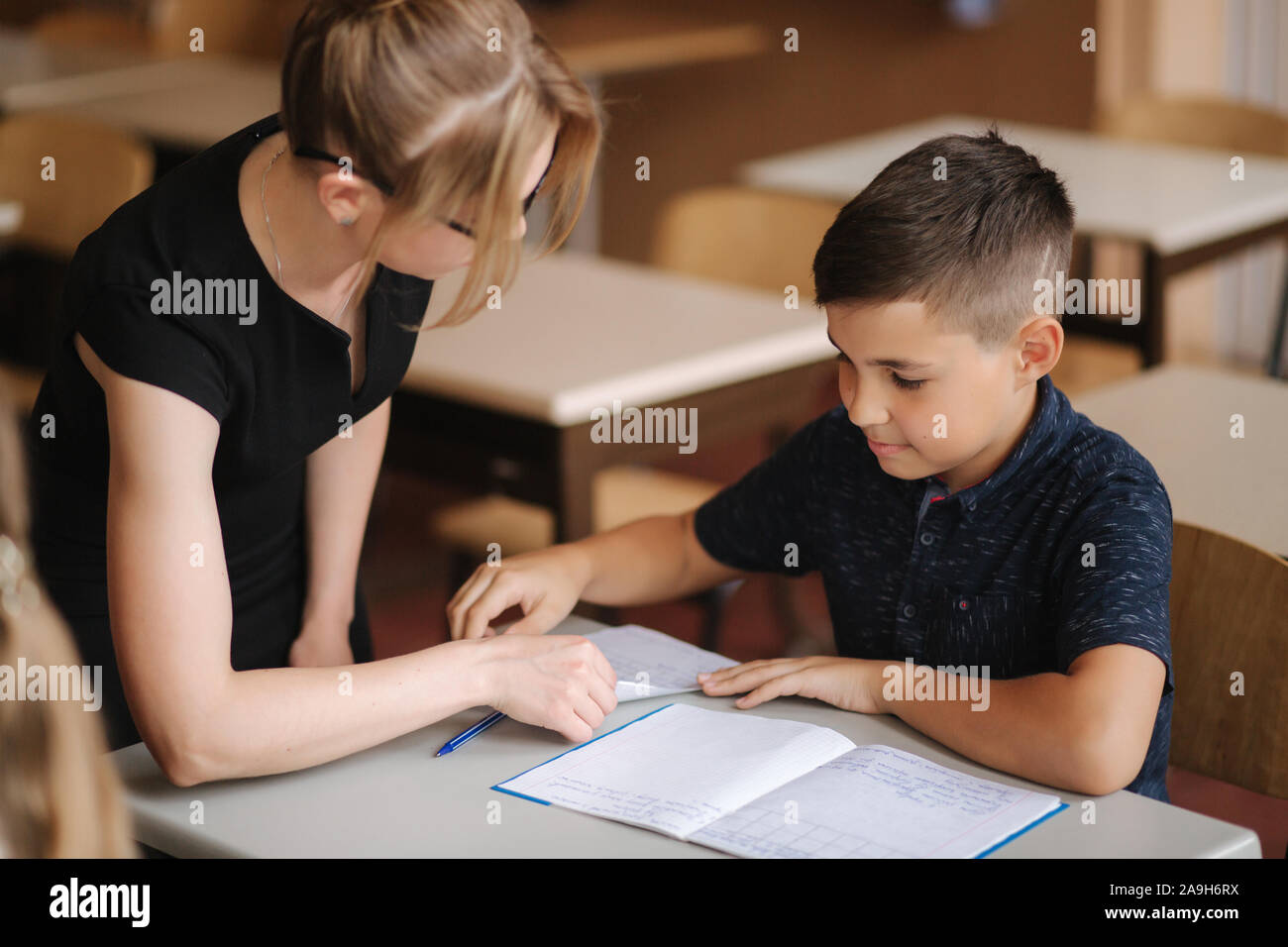 Teacher helping school kids writing test in classroom. education ...
