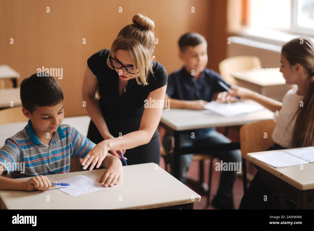 Teacher helping school kids writing test in classroom. education ...