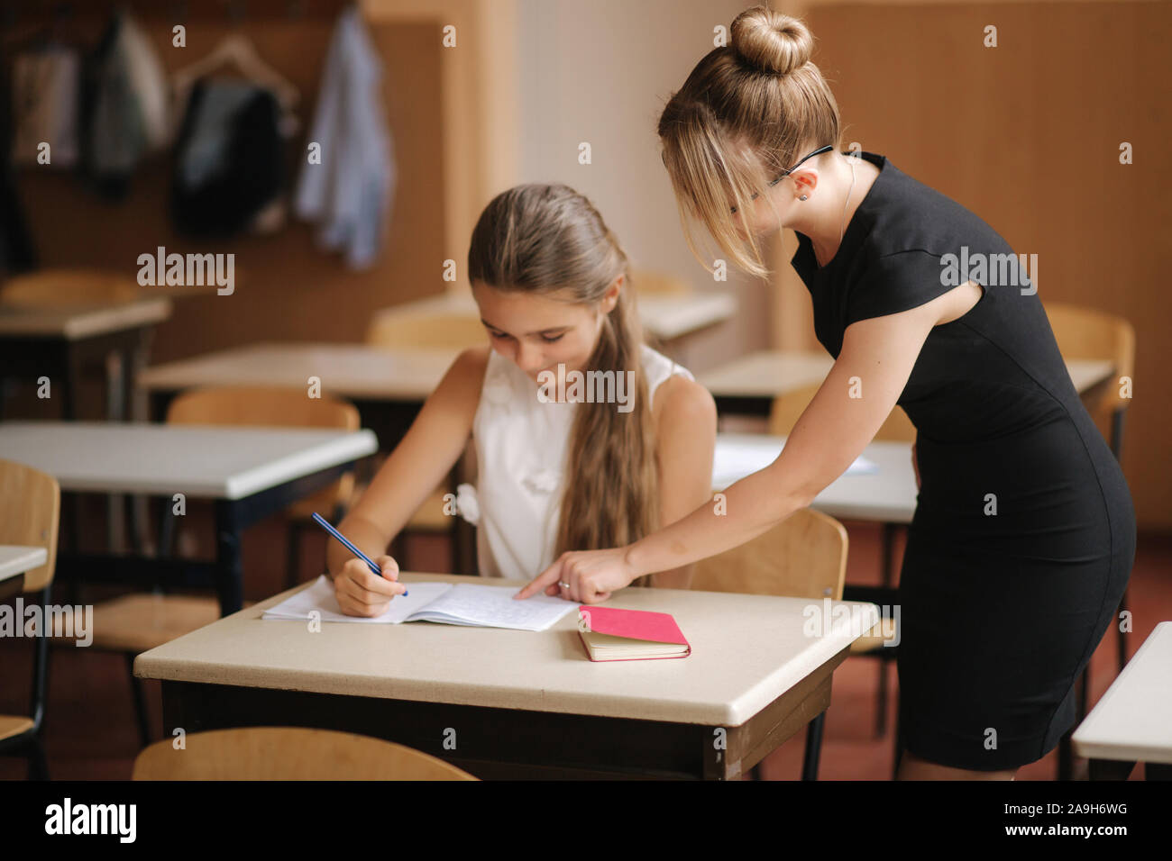Teacher helping school kids writing test in classroom. education ...