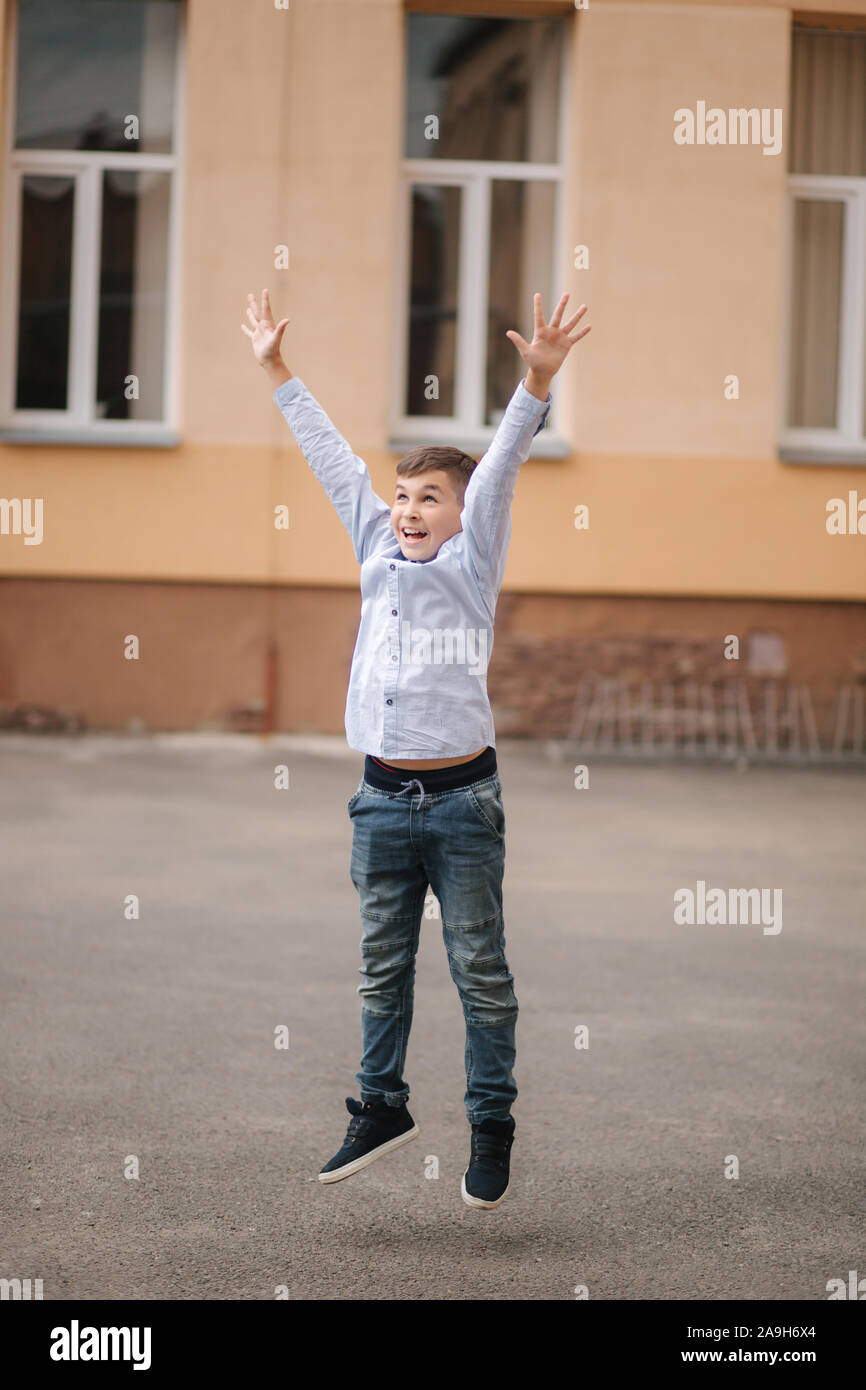 Happy boy jump and raises hands up. Background of school Stock Photo ...