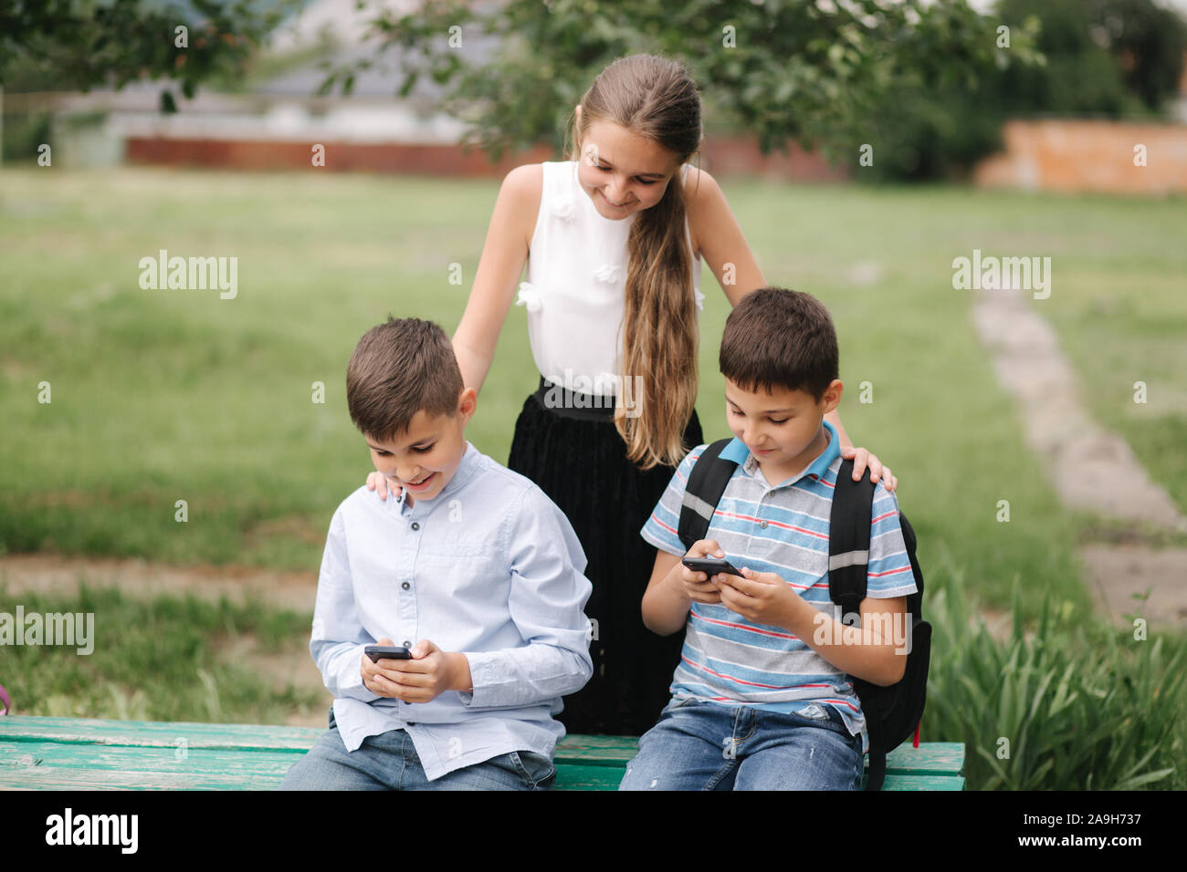 Two boys and girl use their phones during school breack. Cute boys ...