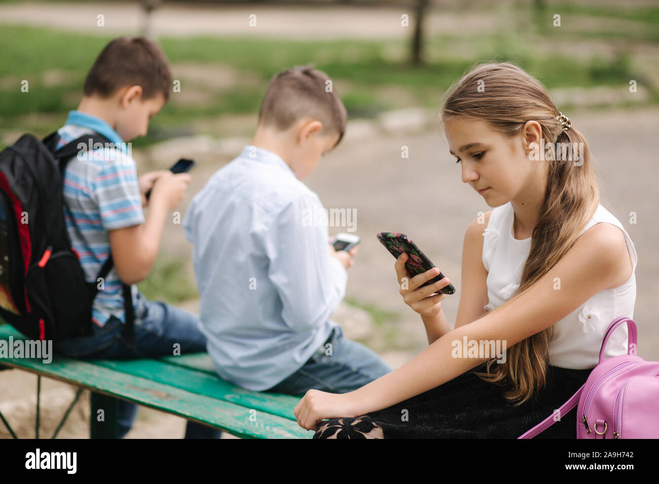 Two boys and girl use their phones during school breack. Cute boys ...