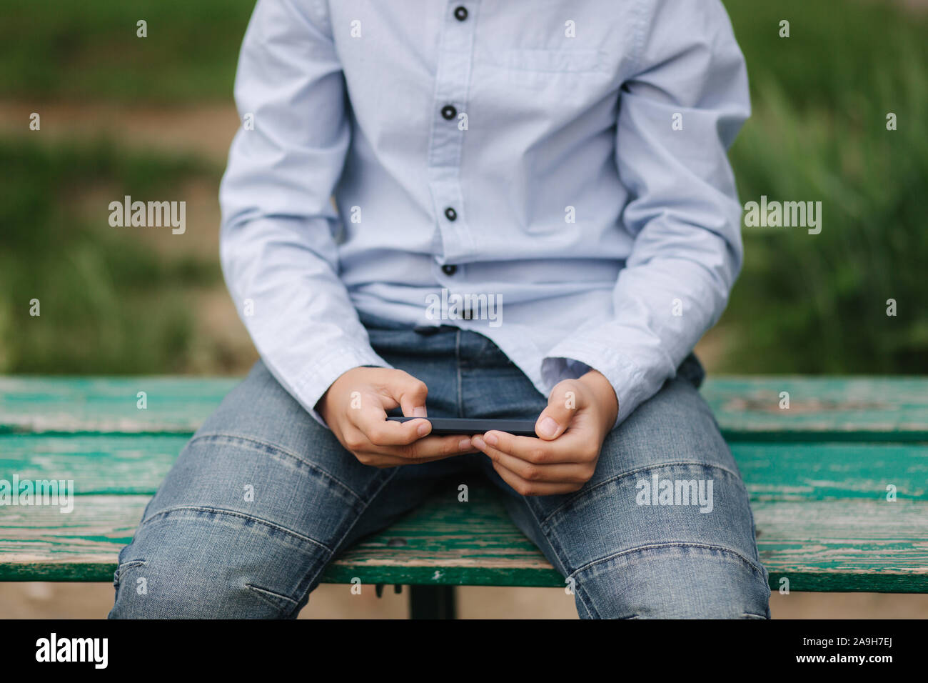 Young boy sitting on the bench and play online games during school ...