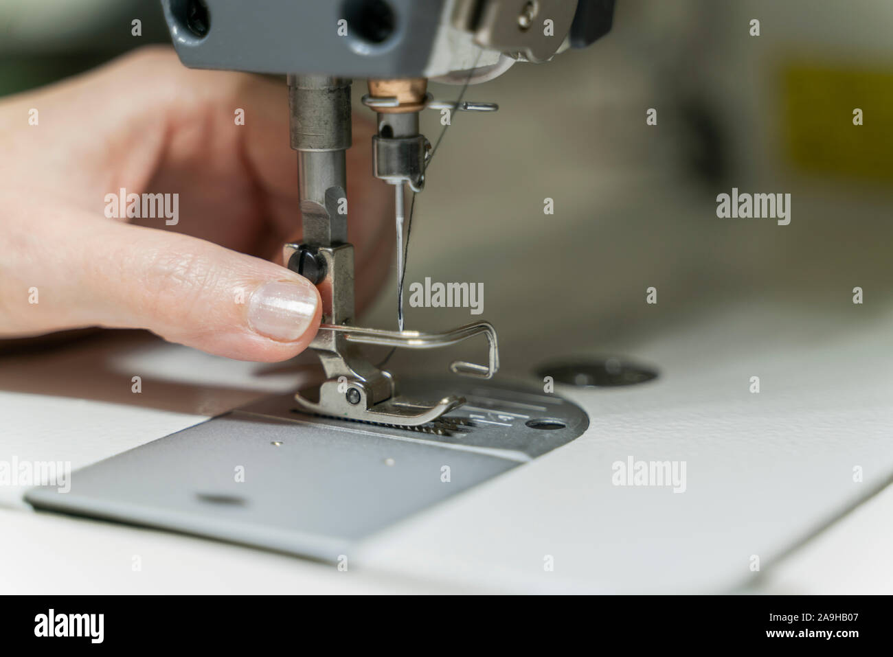 Seamstress sets up sewing machine to make a dress. Close-up depicts ...