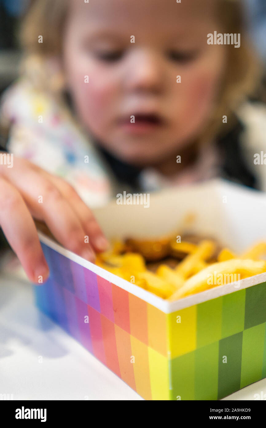 A cute little girl eats her happy meal from the box provided, french ...