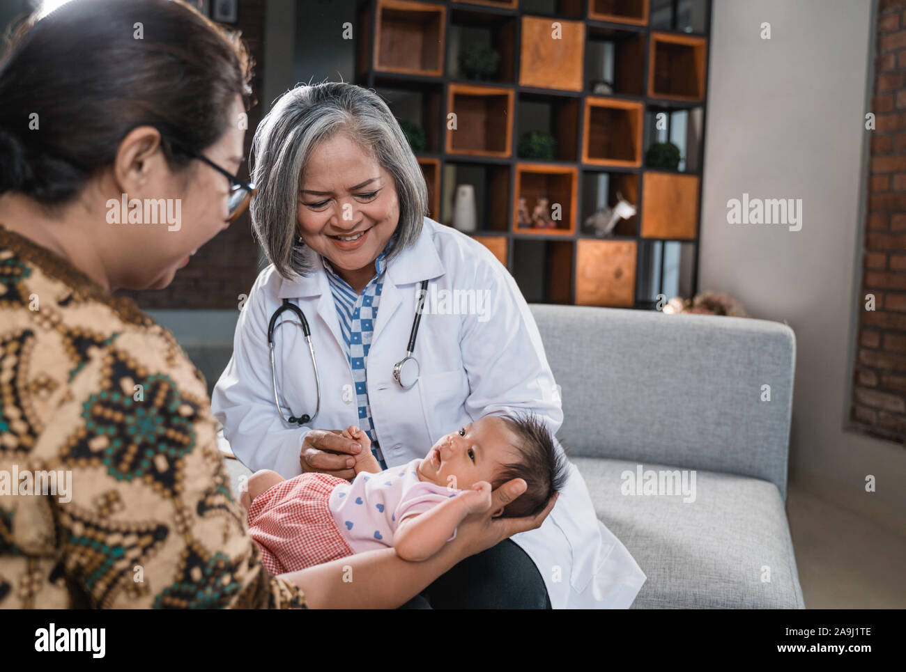 A smiling doctor with a baby and mom hi-res stock photography and ...
