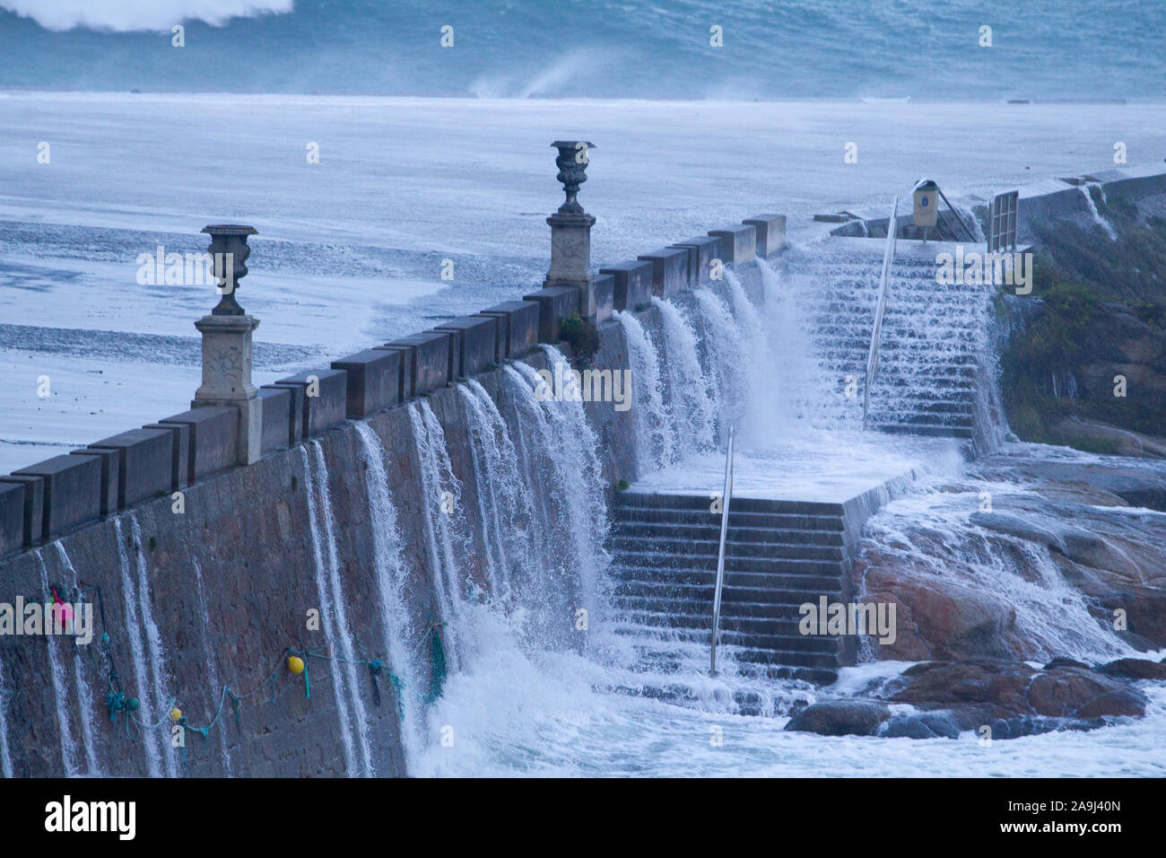 Big waves breaking on the promenade of La Coruña with the buildings of ...