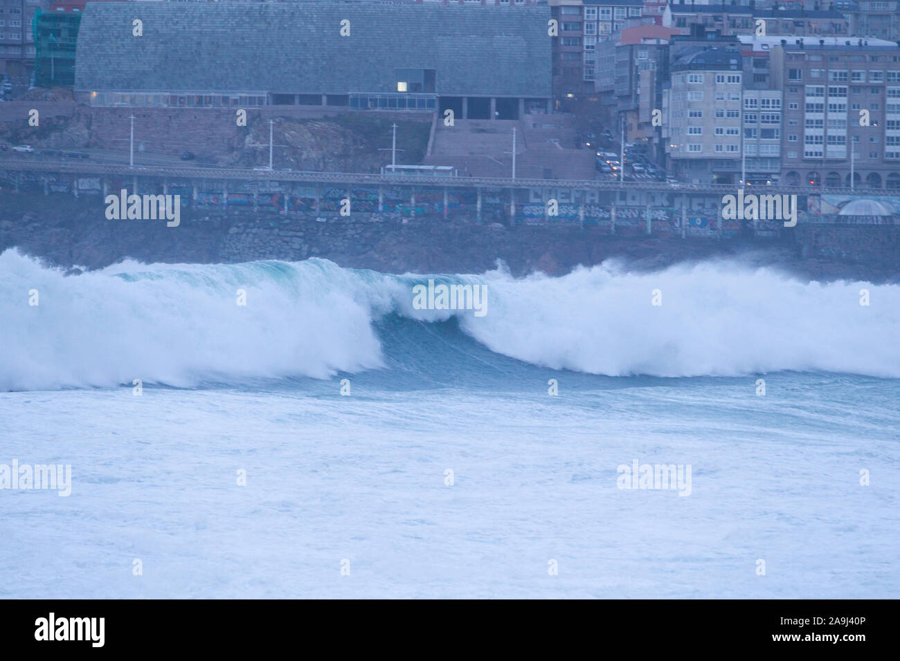 Big waves breaking on the promenade of La Coruña with the buildings of ...