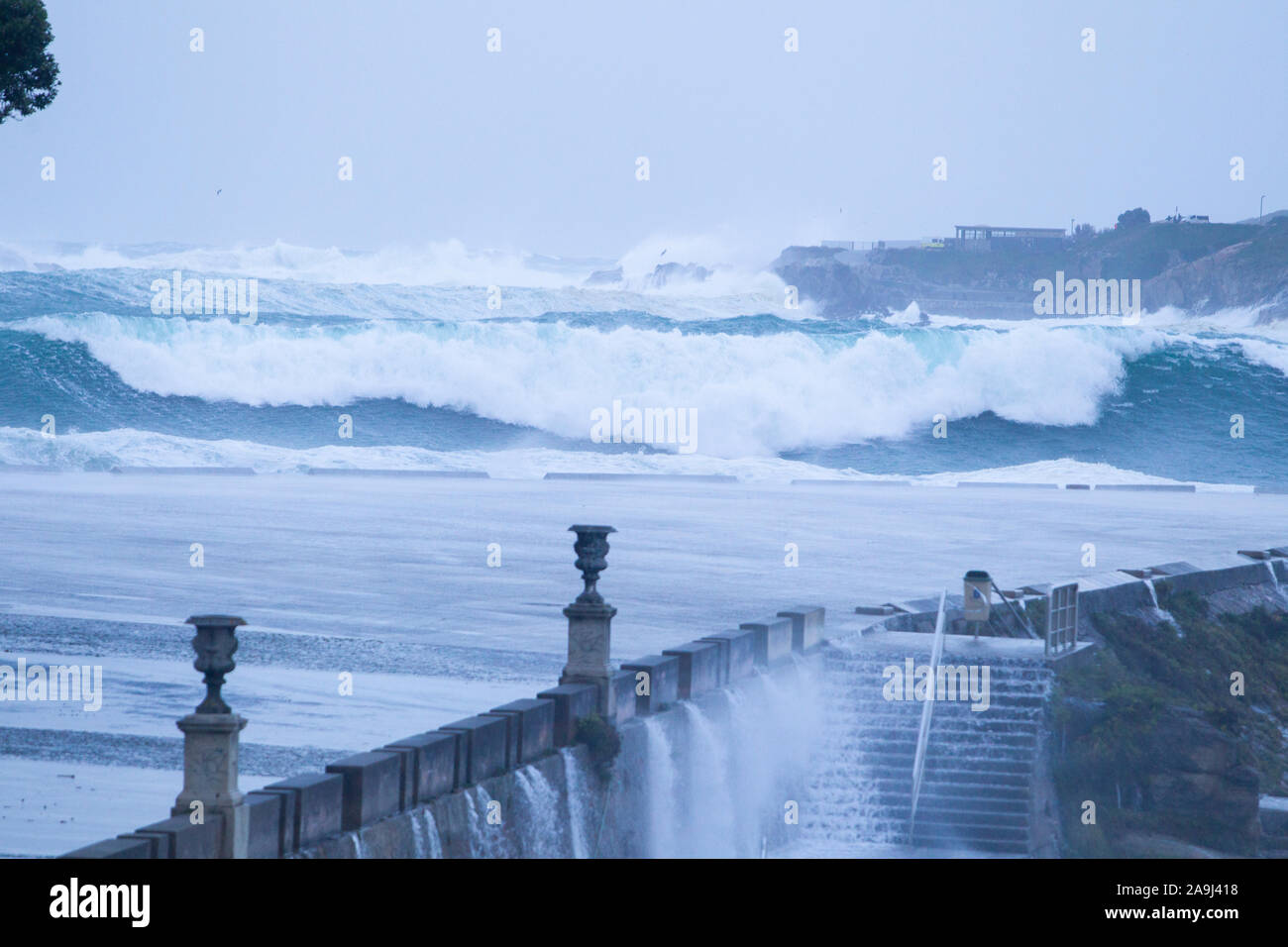 Big waves breaking on the promenade of La Coruña with the buildings of ...