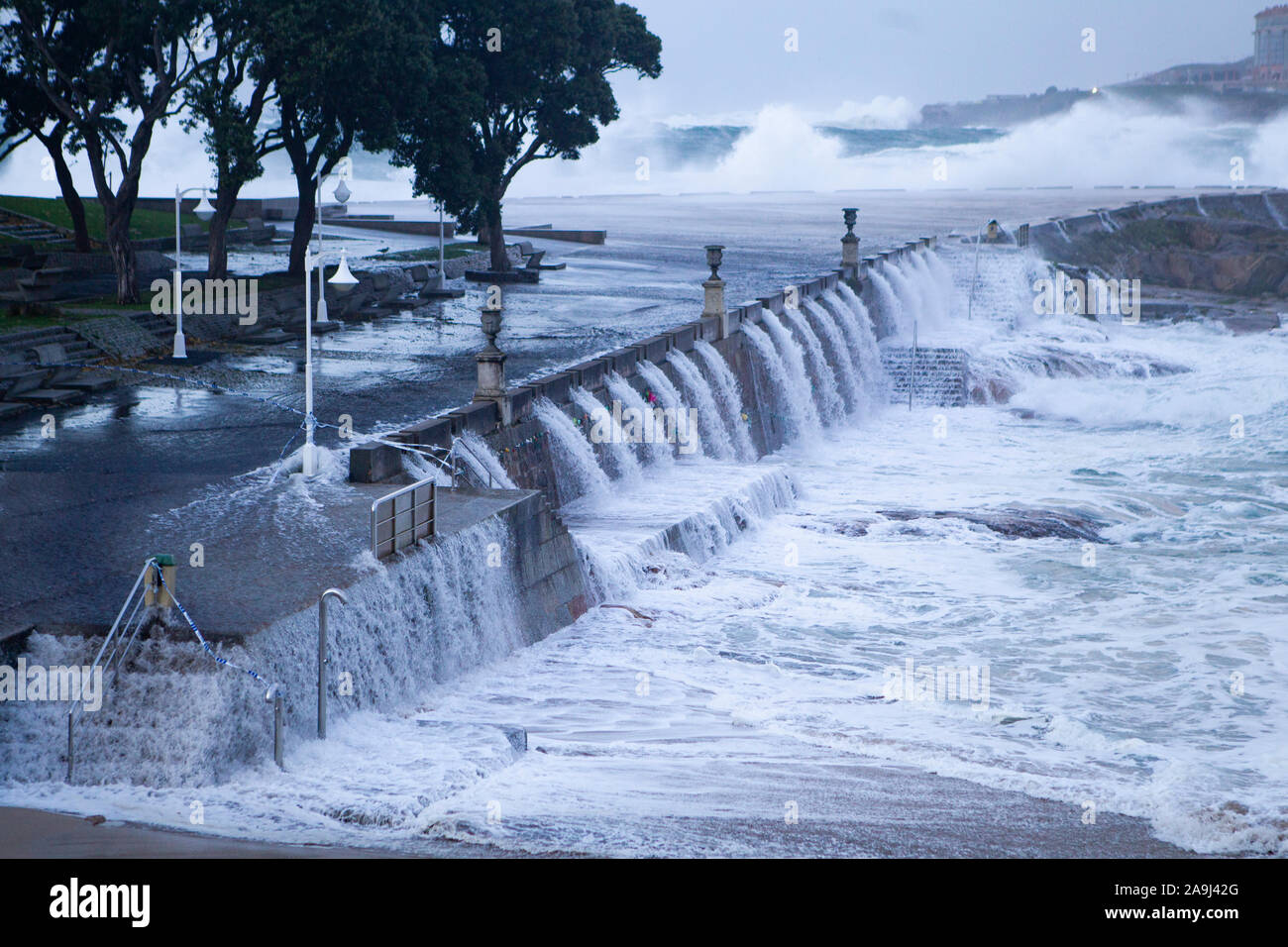 Big waves breaking on the promenade of La Coruña with the buildings of ...
