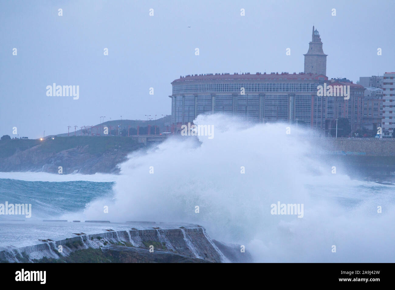 Big waves breaking on the promenade of La Coruña with the buildings of ...