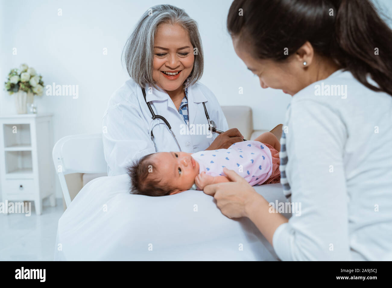 A smiling doctor with a baby and mom hi-res stock photography and ...