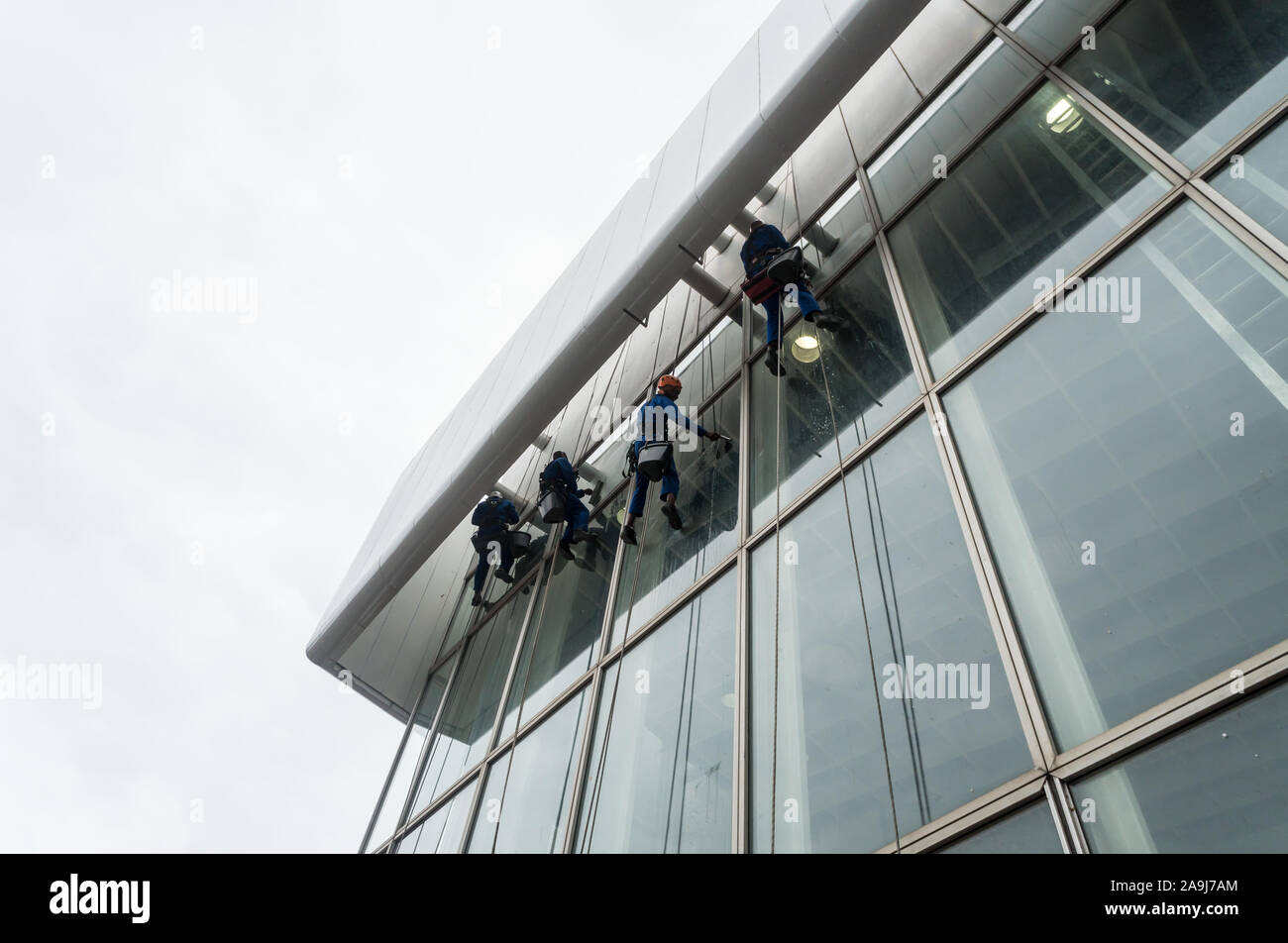 African men window washers or cleaning team suspended on ropes and ...