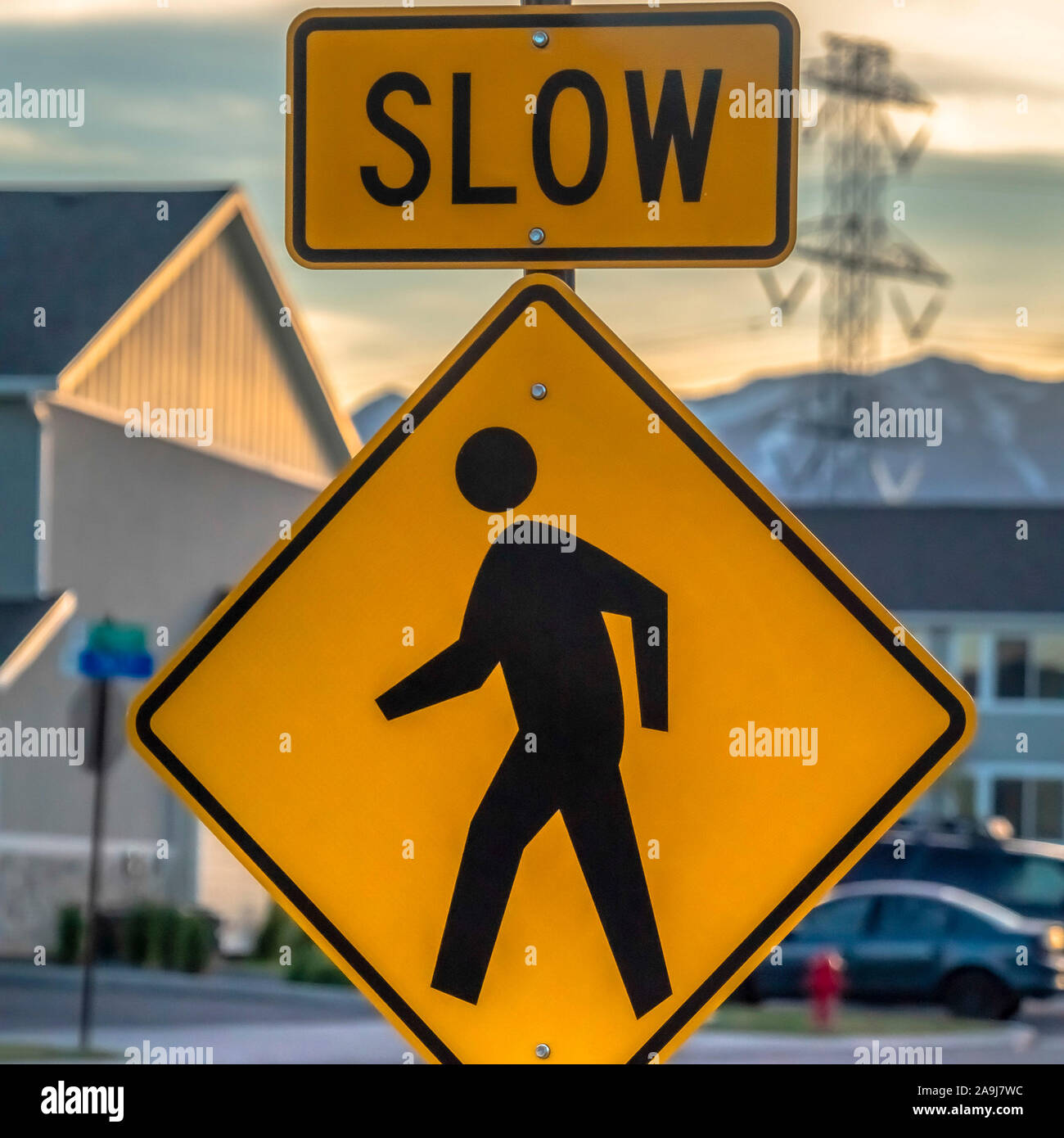 Square Pedestrian crossing road sign against houses vehicles mountain ...