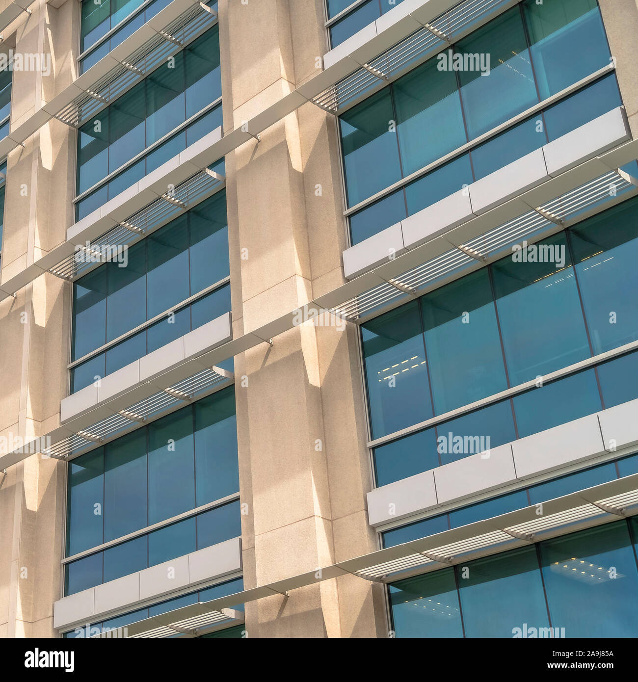 Square Modern building facade close up with glass windows and sunlit ...