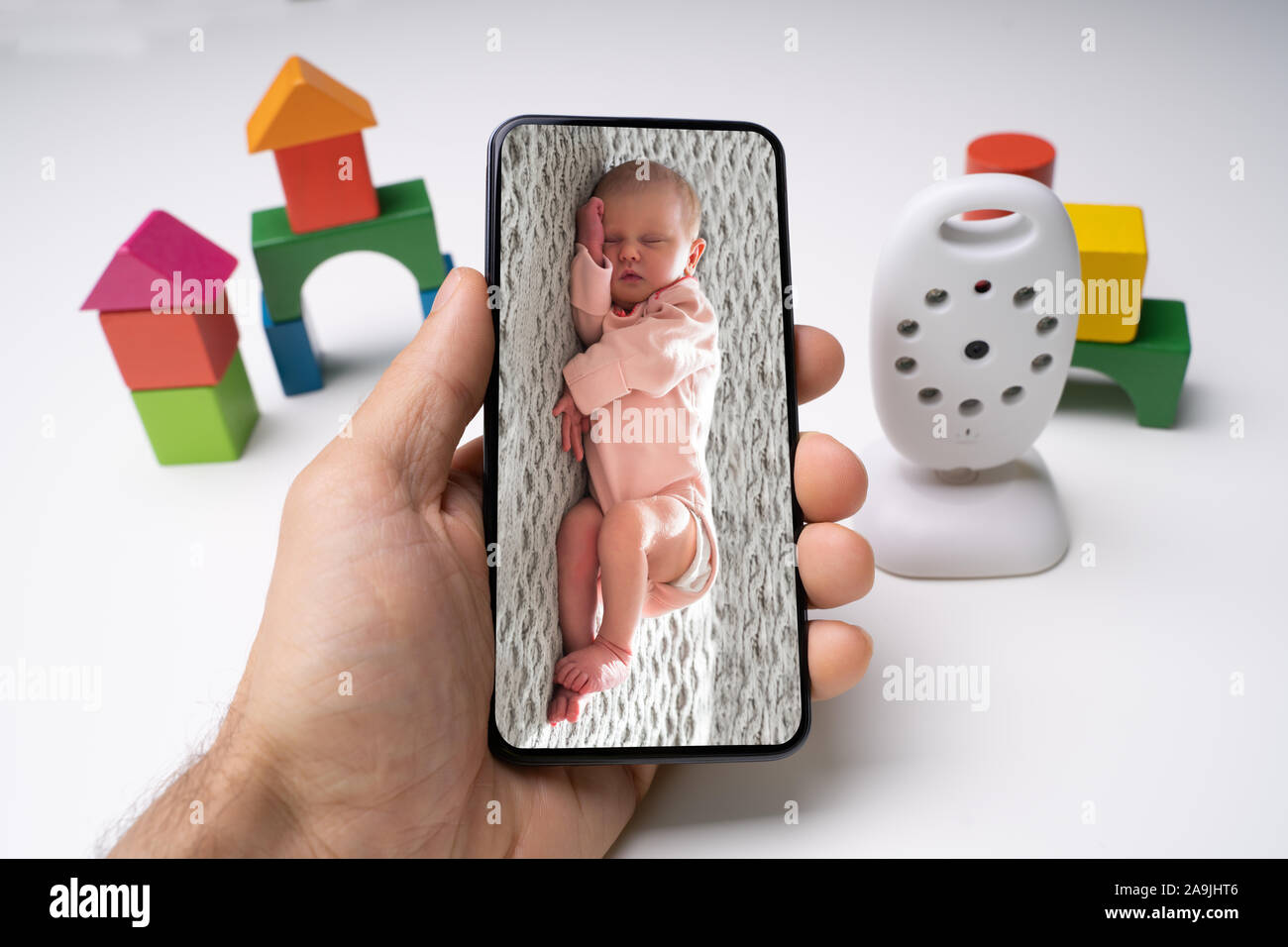 Person's Hand Holding Mobile Phone With Baby Image Near Wireless Camera ...