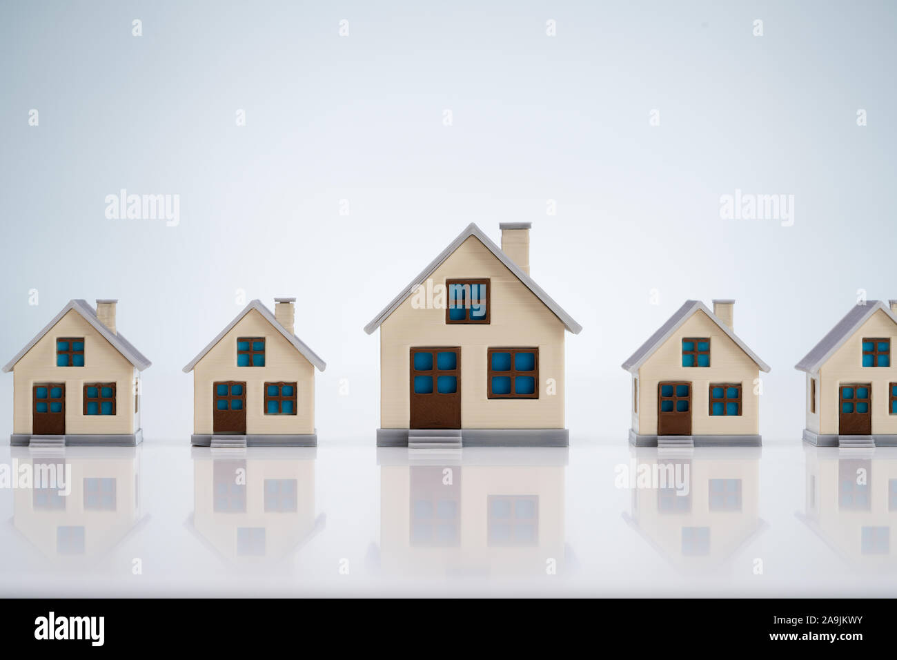 Small Beautiful House Models Arrange In A Row Over Reflective Table ...