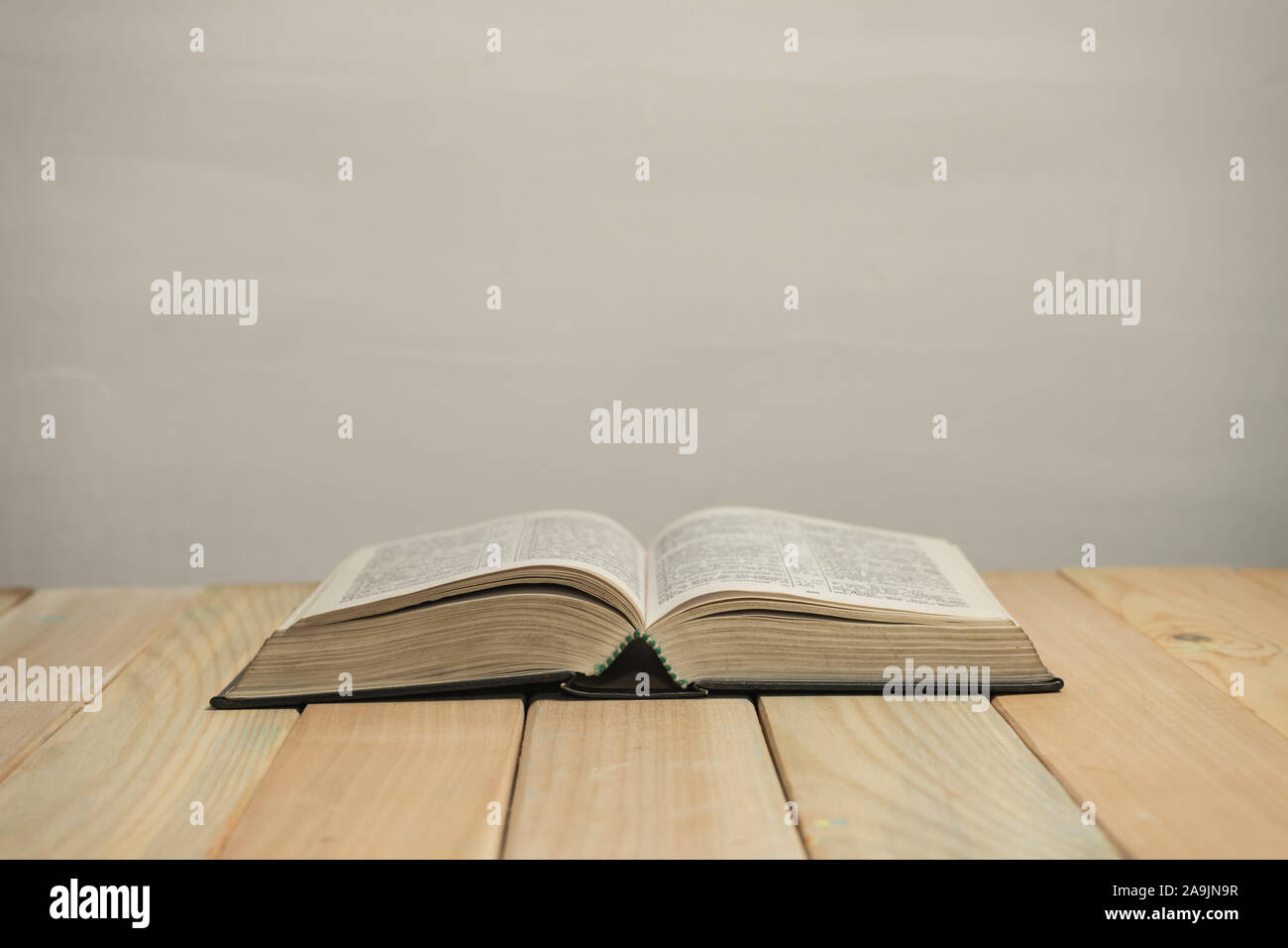 Open Bible on a old wooden table and white wall background. Religion ...