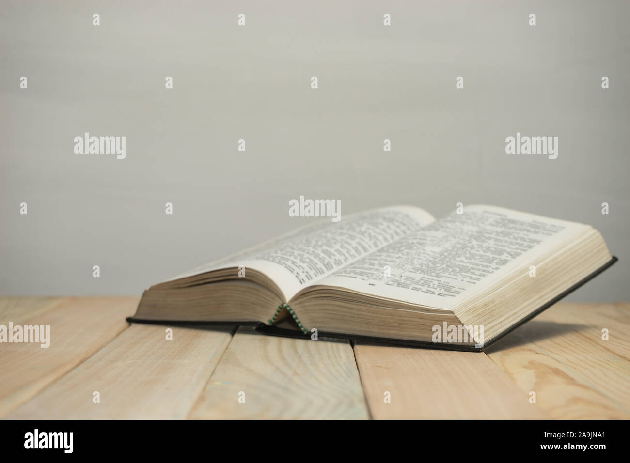 Open Bible on a old wooden table and white wall background. Religion ...