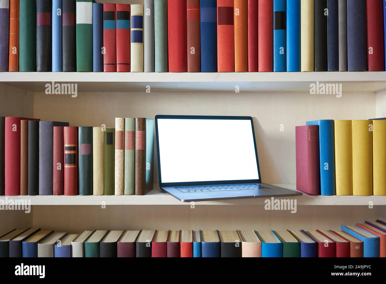 Laptop with blank screen in bookshelf with colorful book covers Stock ...