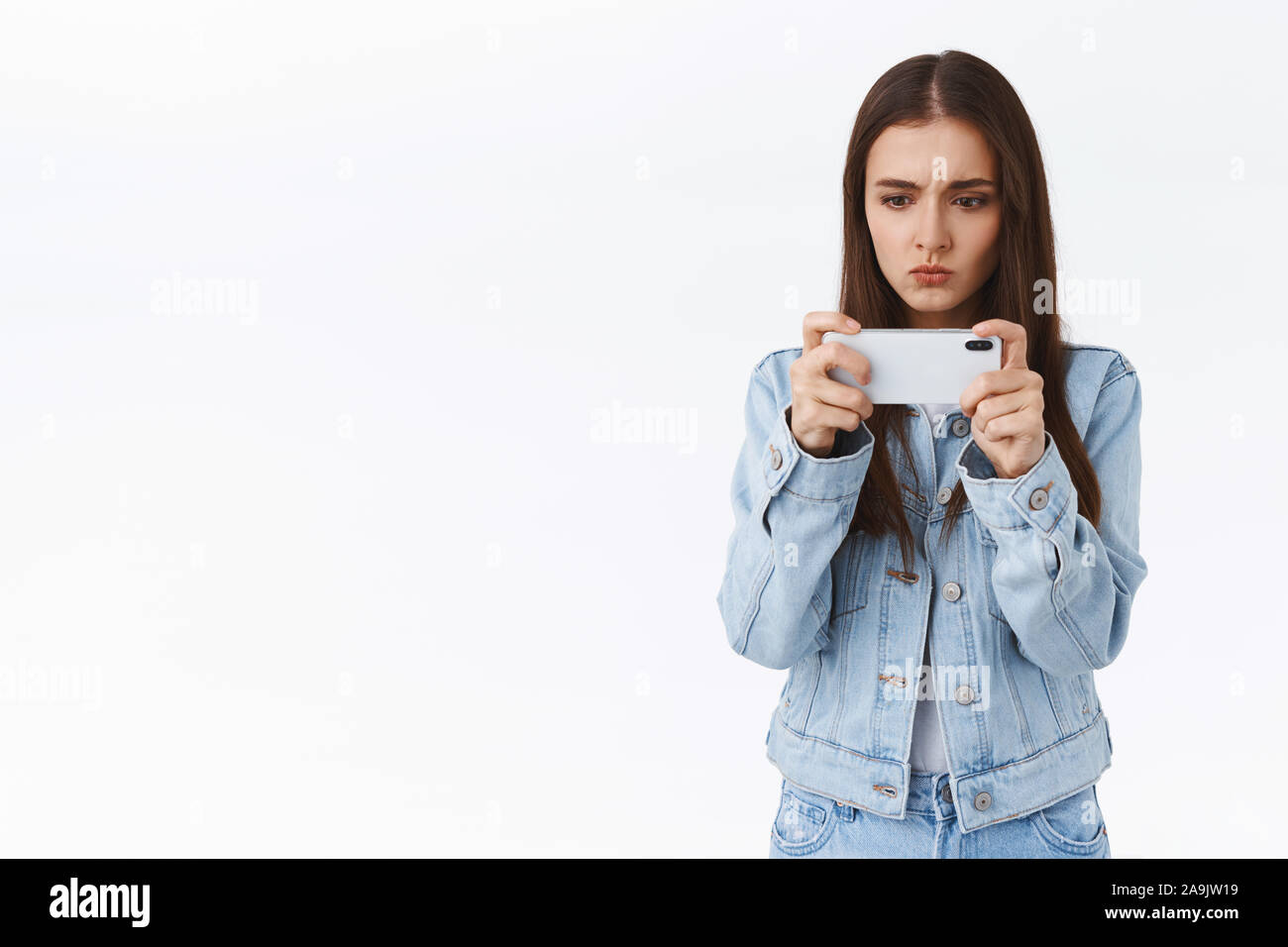 Serious-looking cute and feminine caucasian woman in denim, holding ...