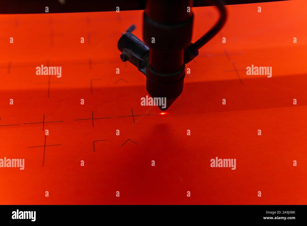 laser cutting head of an industrial machine cuts through an orange ...
