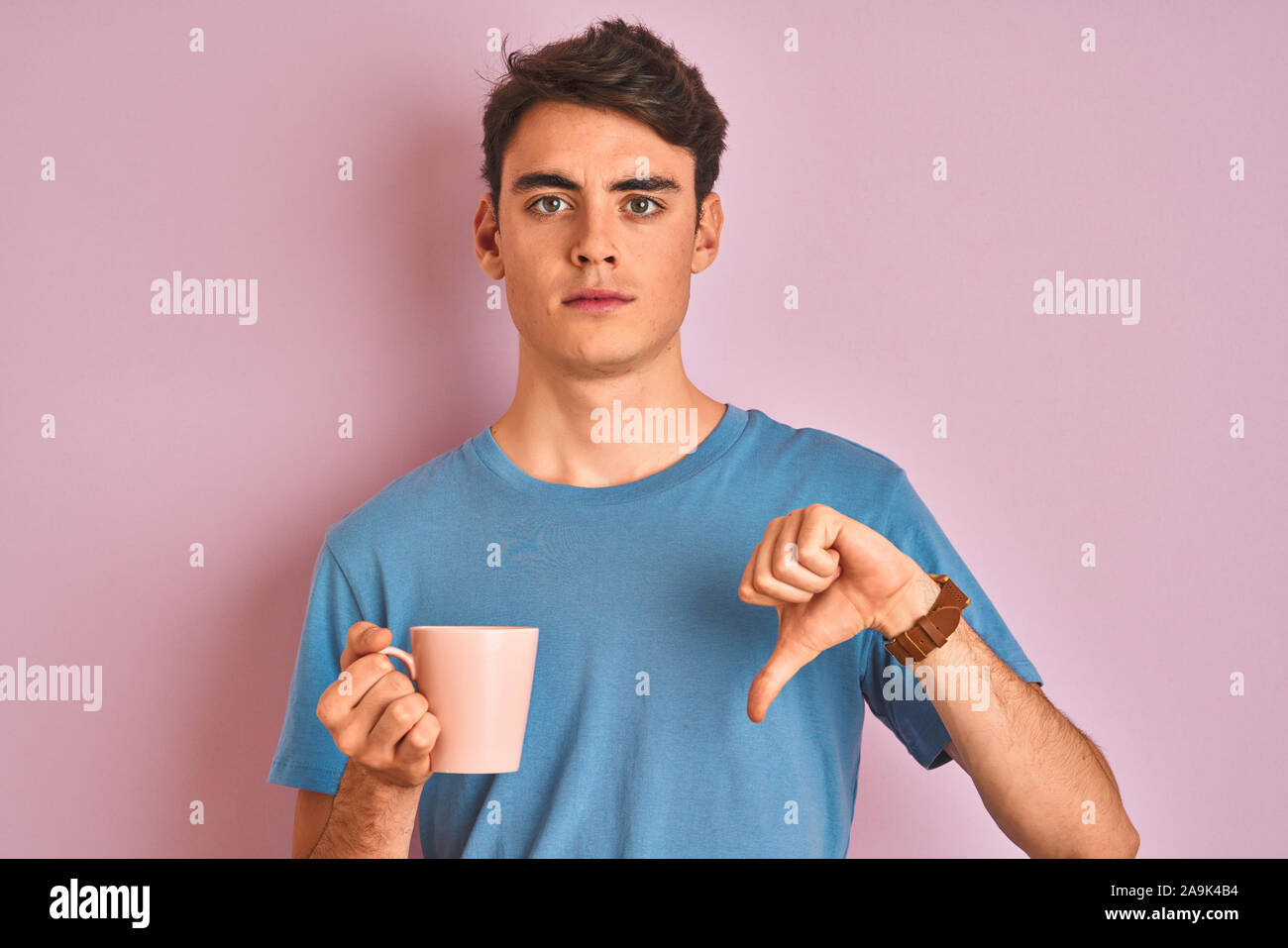 Teenager boy drinking a cup of coffee over isolated pink background ...