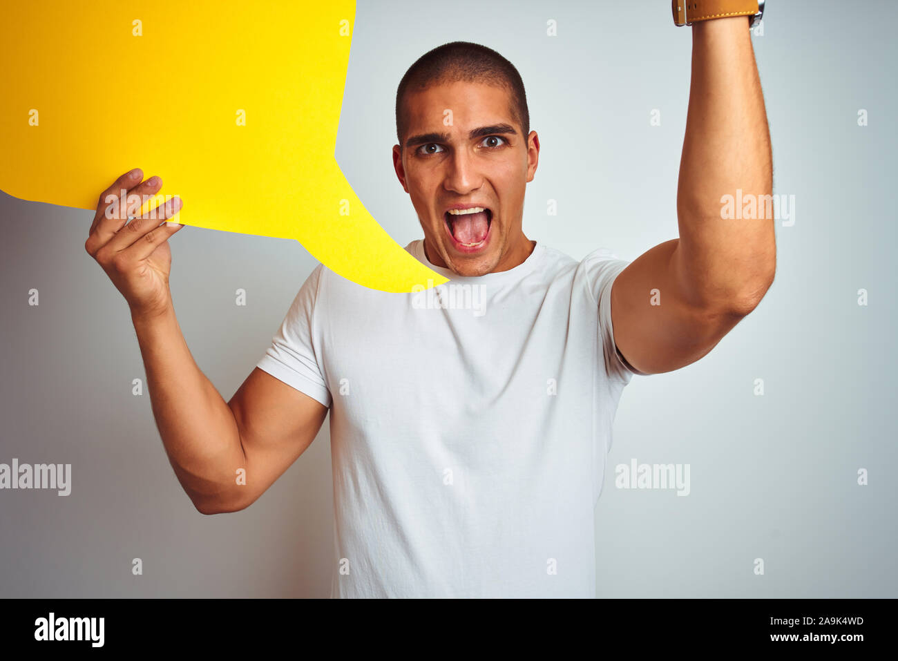 Young man holding yellow speech bubble over white isolated background ...
