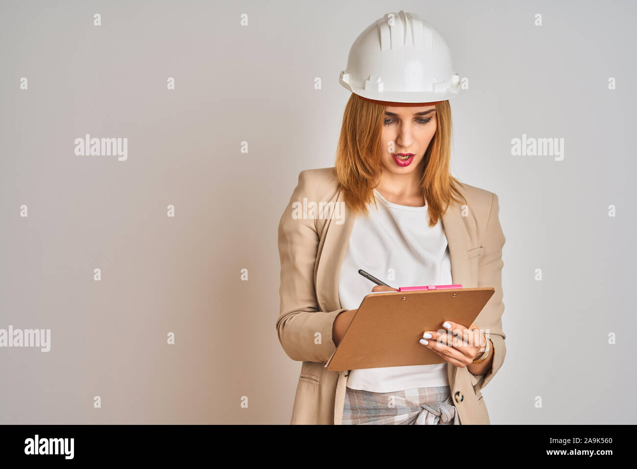 Redhead caucasian business woman wearing safety helmet and holding ...