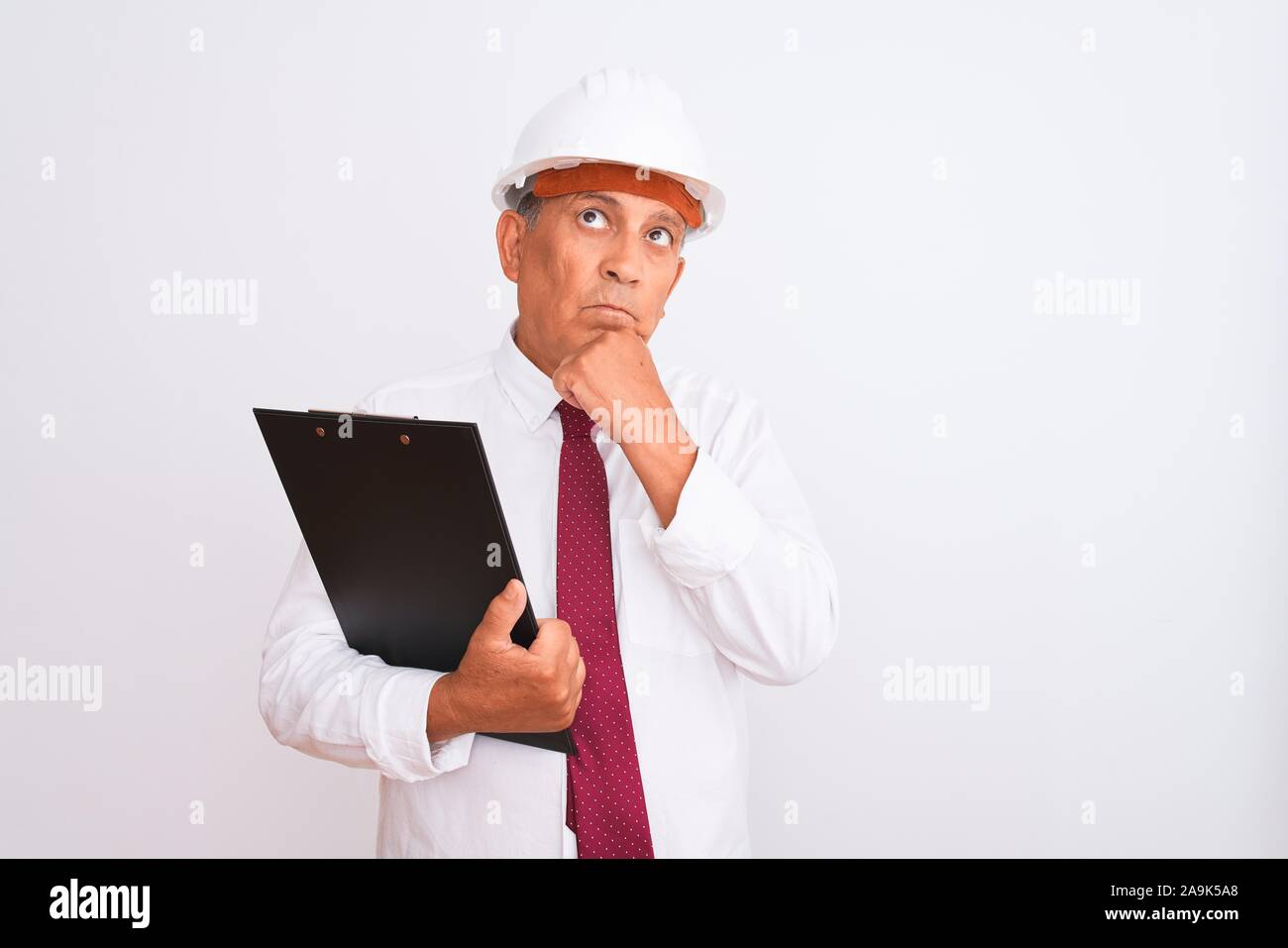 Senior architect man wearing security helmet holding clipboard over ...