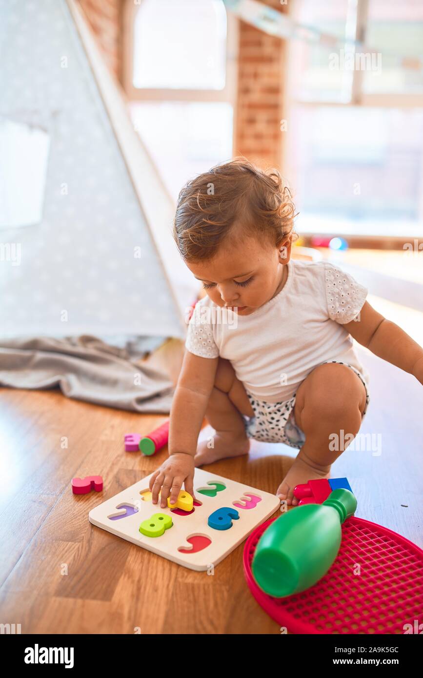 Adorable toddler learning numbers using maths puzzle around lots of ...