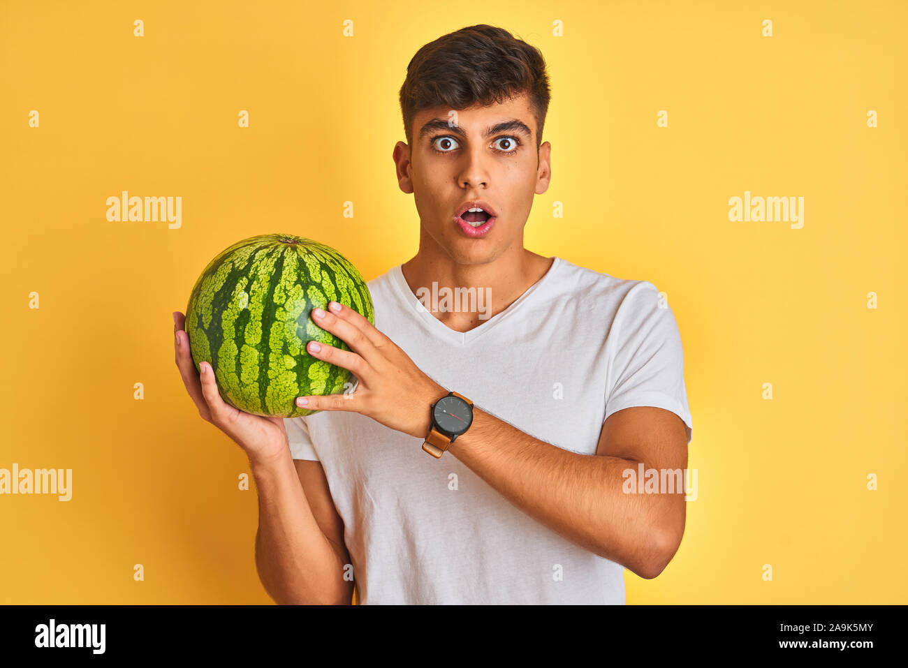 Young indian shopkeeper man holding watermelon standing over isolated ...